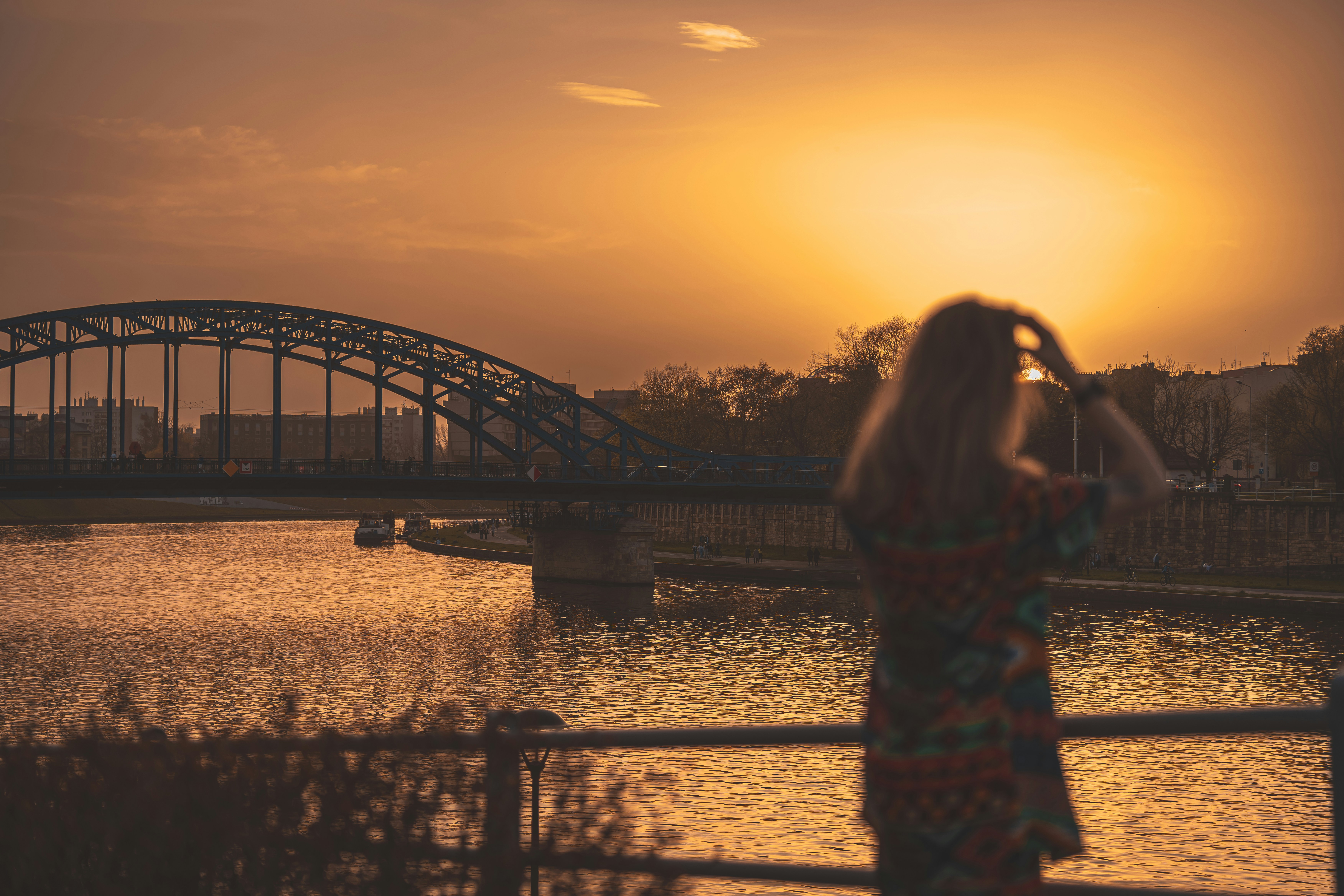 A woman standing on a bridge looking at the sun photo – Free Woman ...