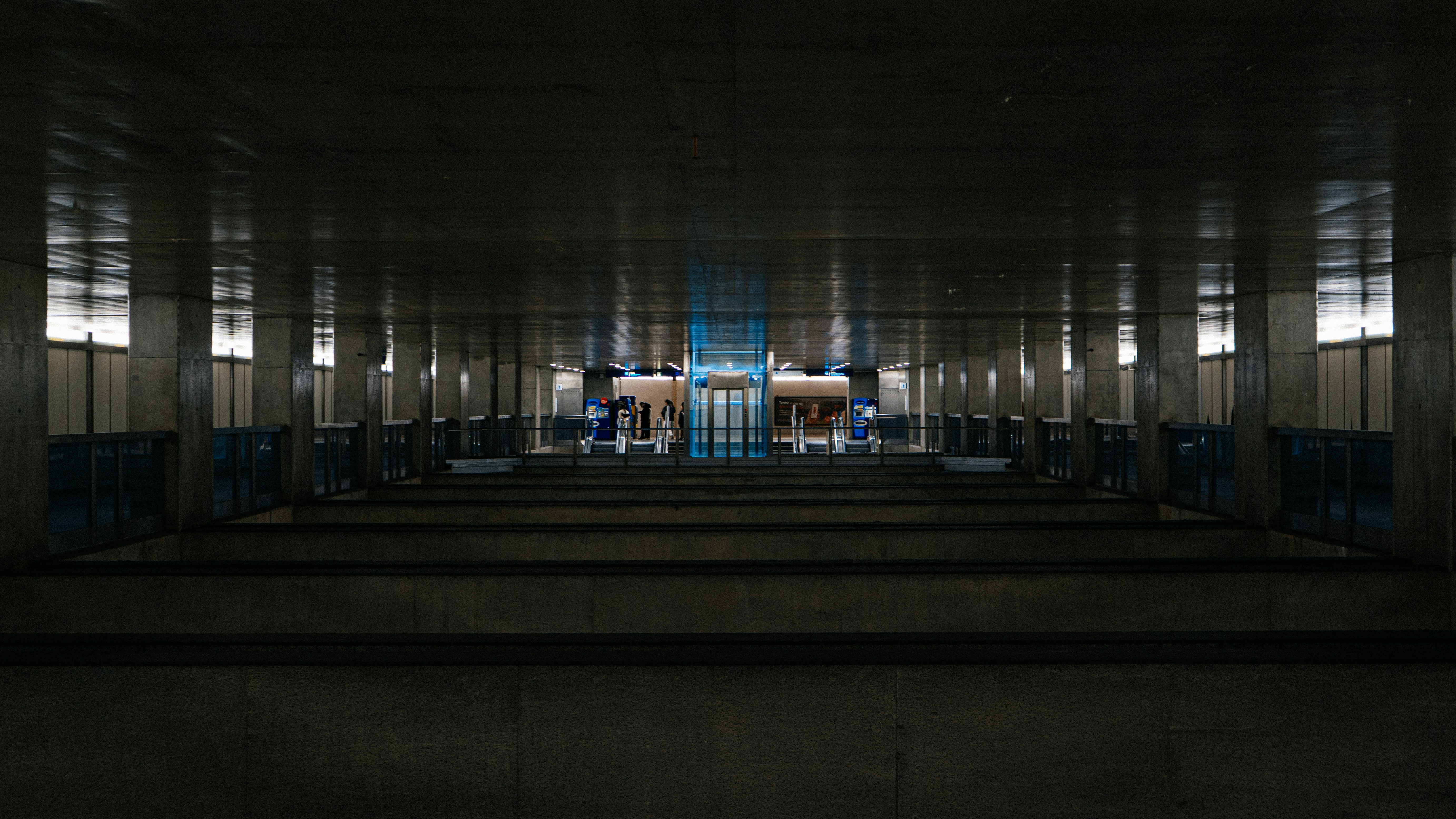 Dimly lit underground station with symmetrical platforms and overhead reflections.