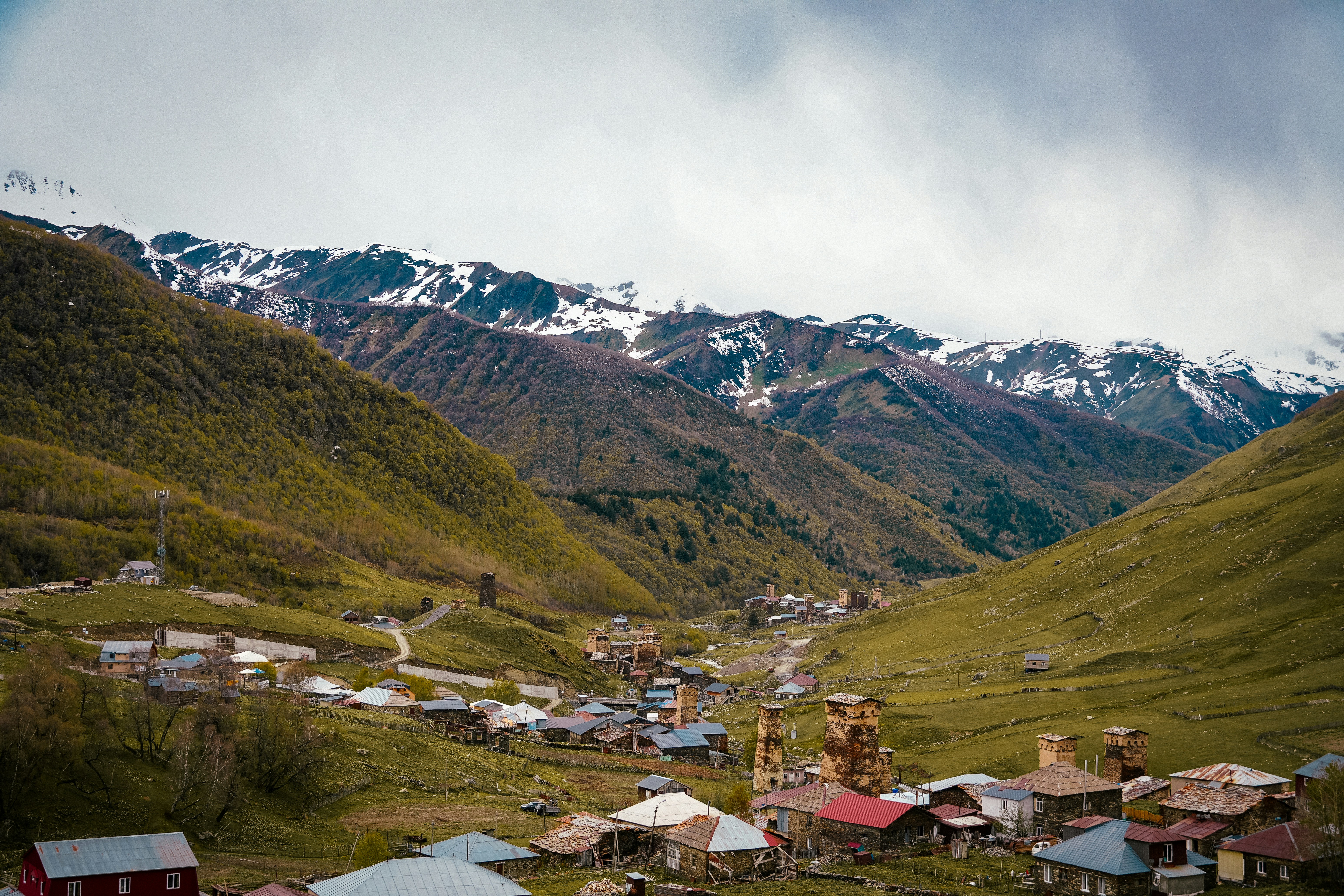 Ushguli is one of the highest continuously inhabited settlements in Europe and is famous for its stunning medieval stone towers, traditional Svan architecture, and breathtaking mountainous landscapes. The snow-capped peaks in the background likely belong to the Caucasus Mountains, including Mount Shkhara, the highest peak in Georgia. | A small village in the middle of a valley