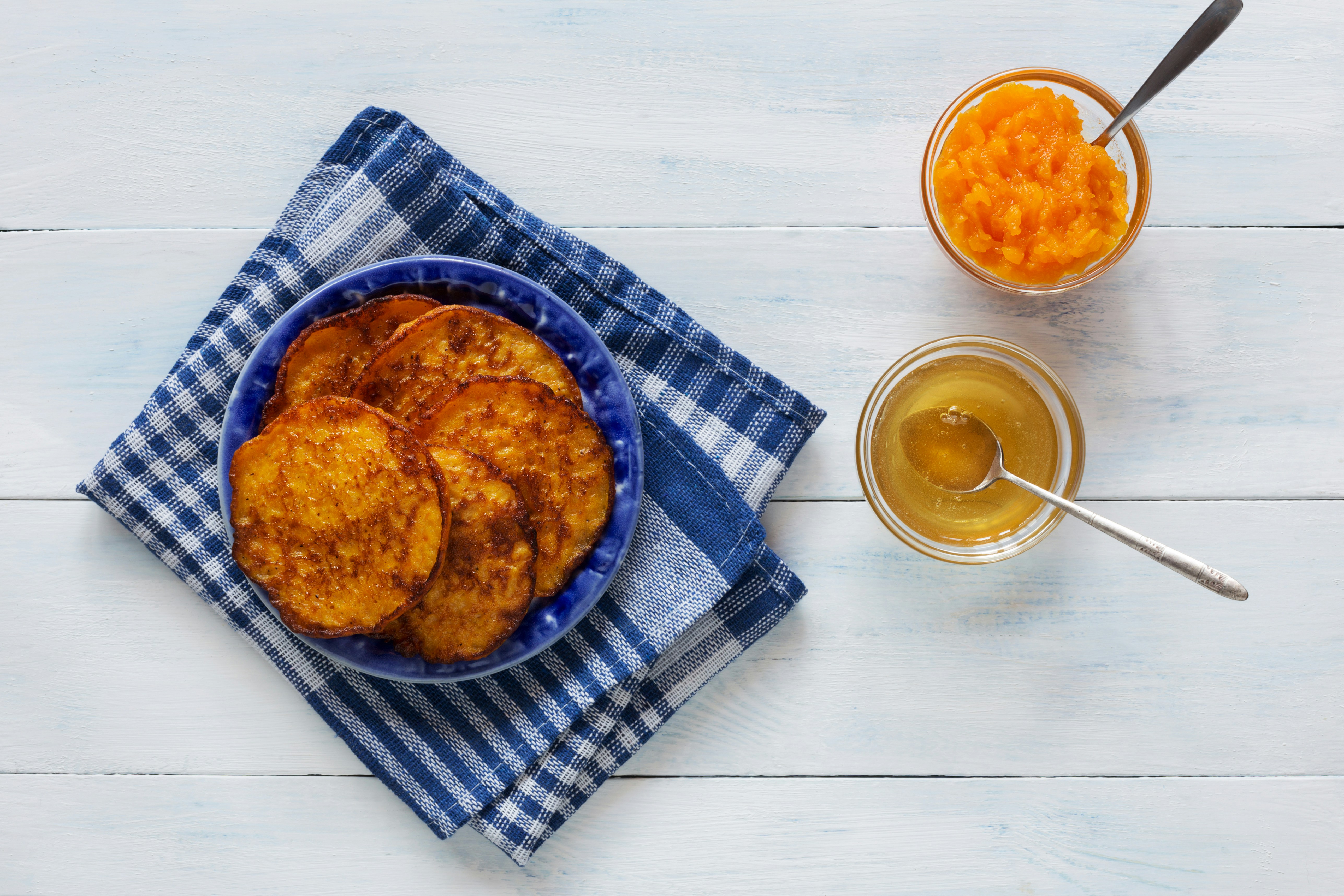 Pumpkin pancakes with honey and tea | A blue plate topped with fried food next to two glasses of orange juice