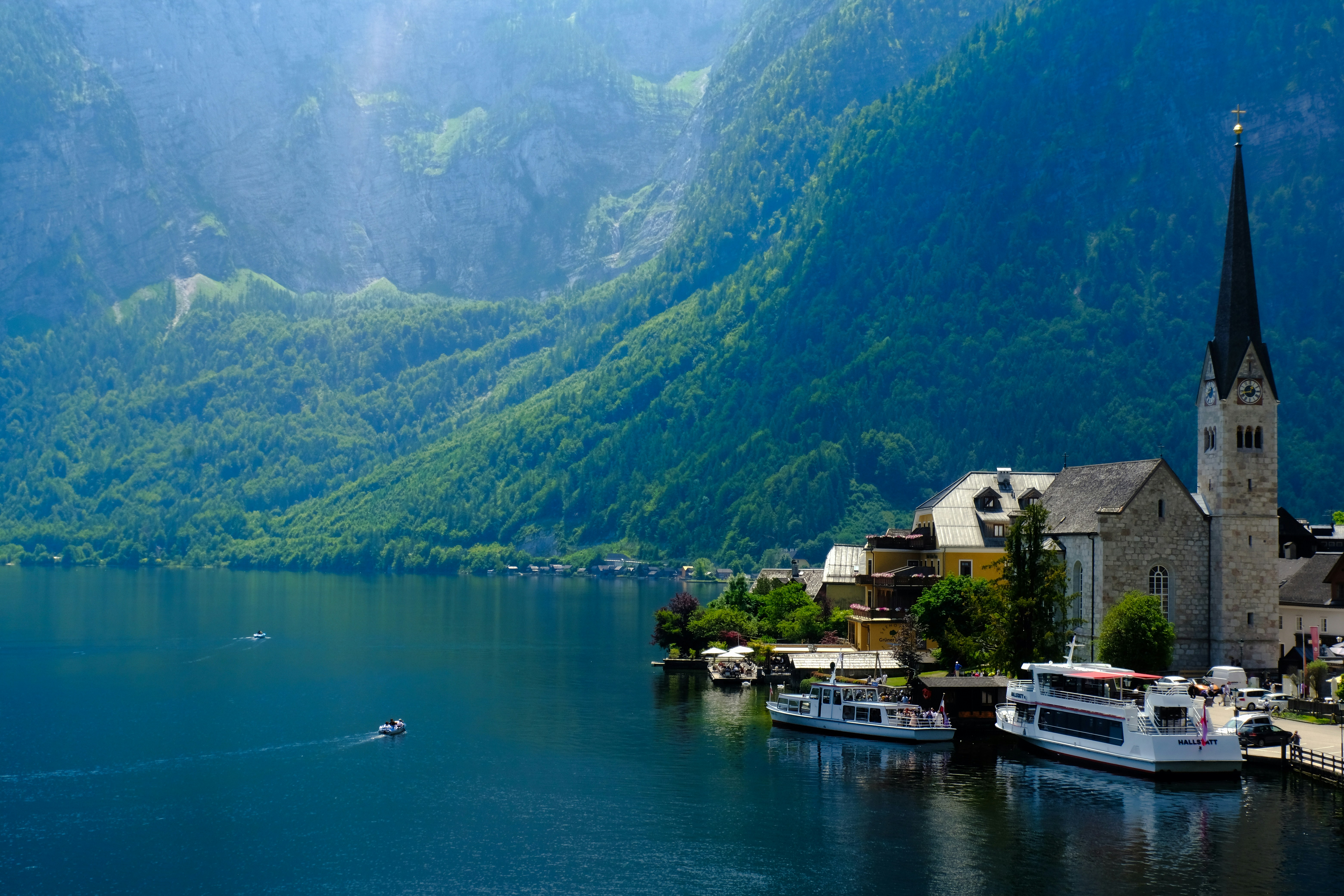Lakeside village of Hallstatt with a historic church and alpine architecture mirrored in a calm lake surrounded by lush mountains.