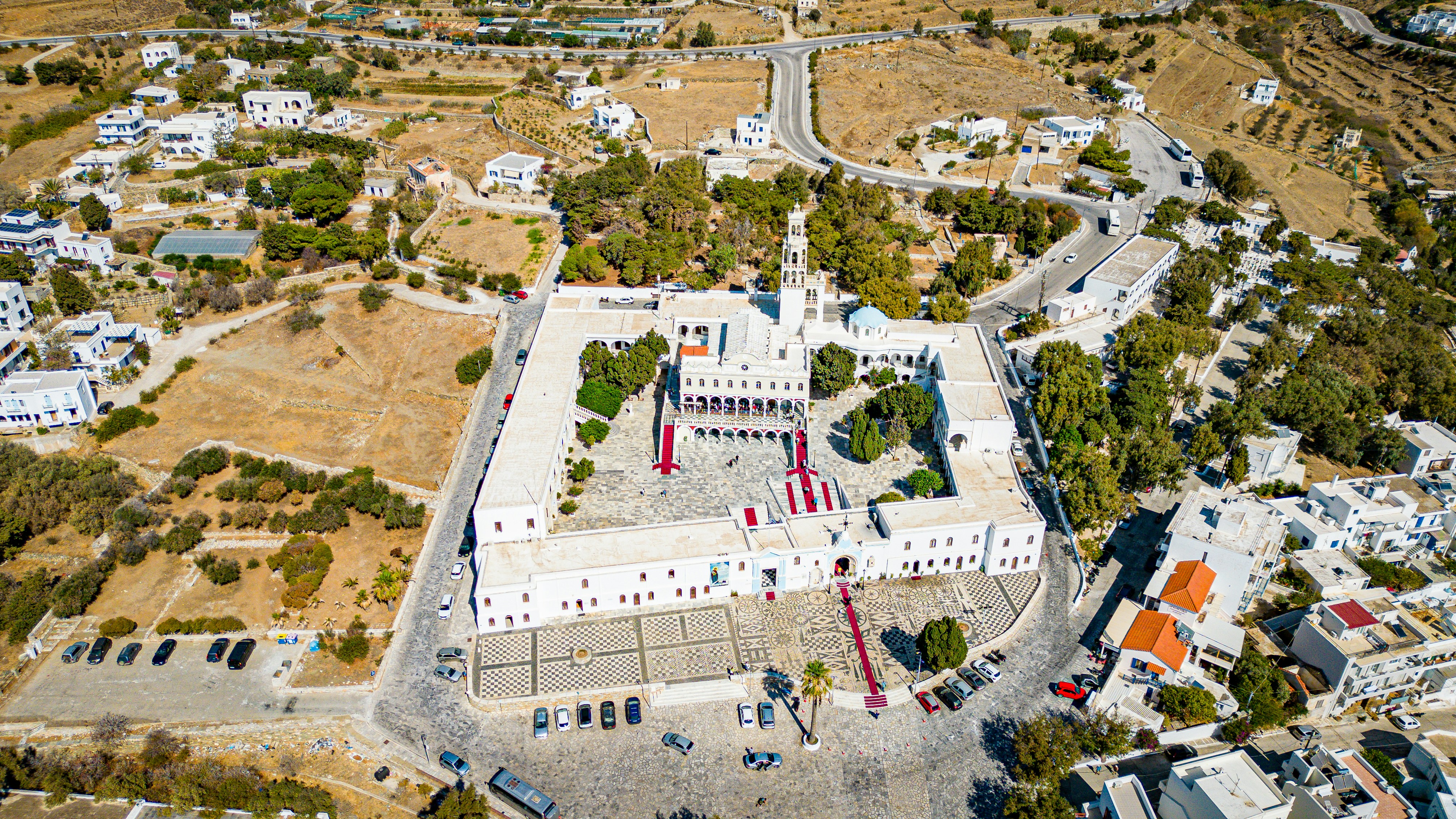 Historic monastery with red carpet amidst arid landscape on Tinos Island.