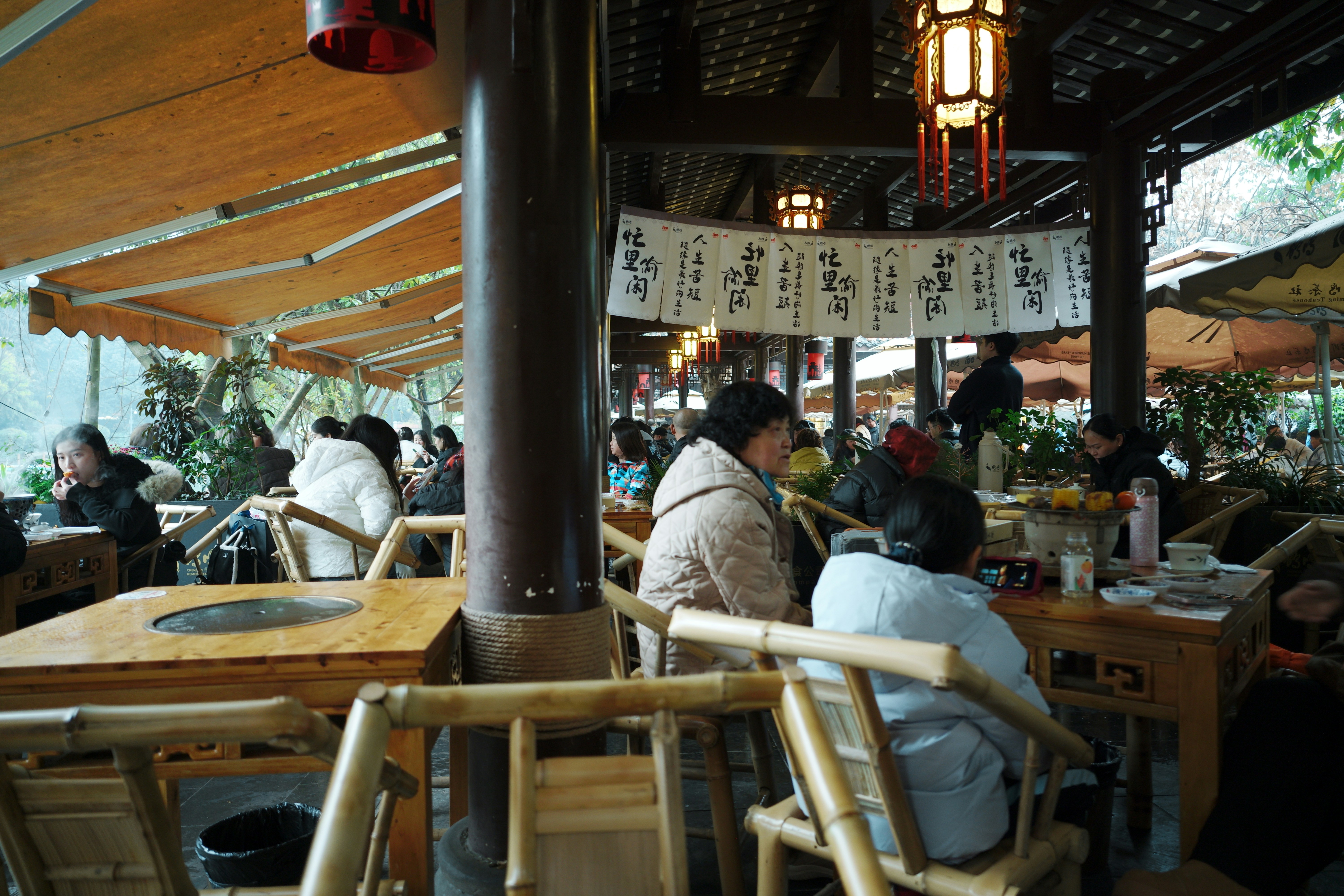 People gathered in a bamboo-themed cafe with warm lighting and outdoor elements.