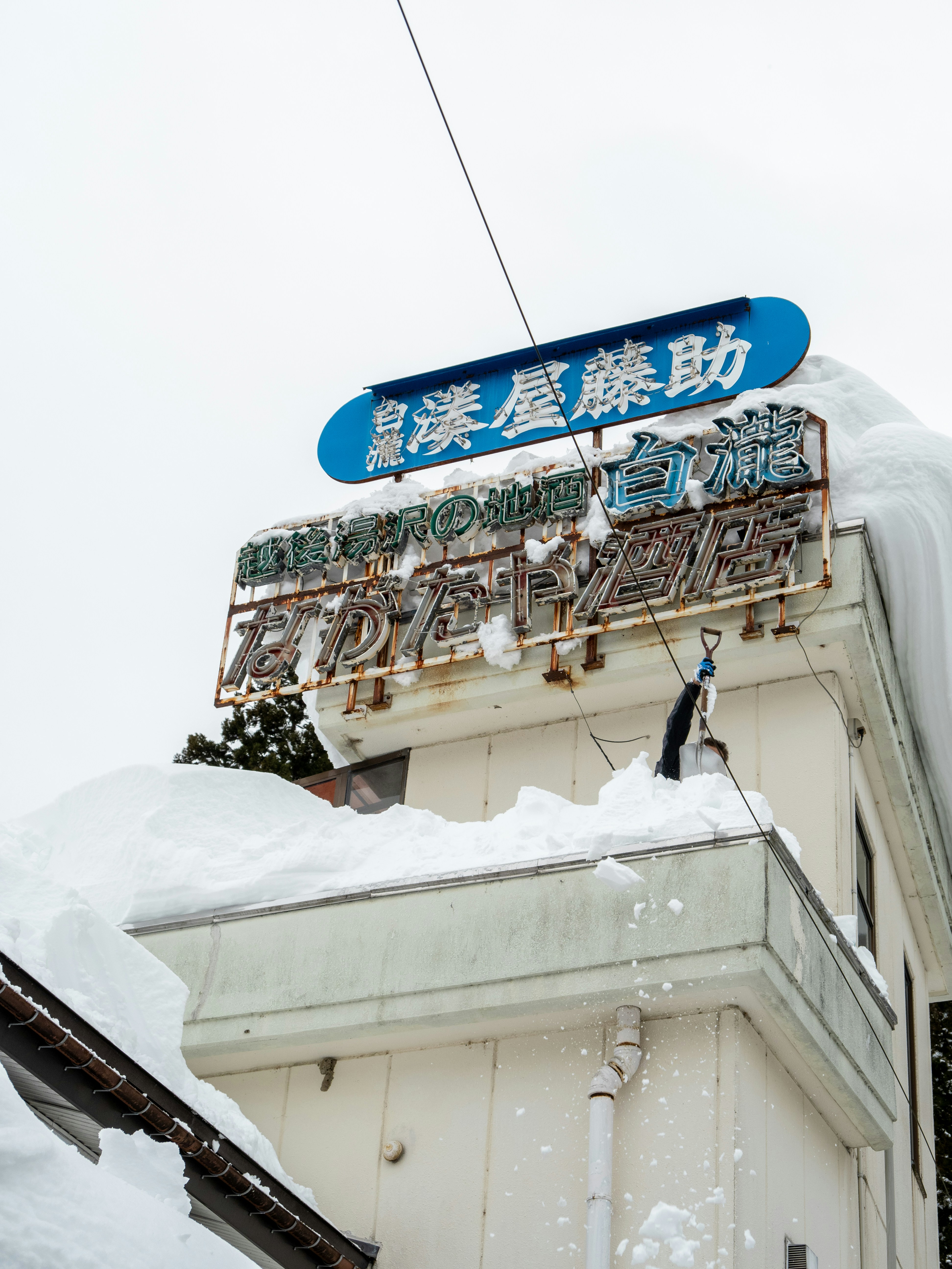 Blue Signboard Crowned by Snow on a Quiet Alpine Building