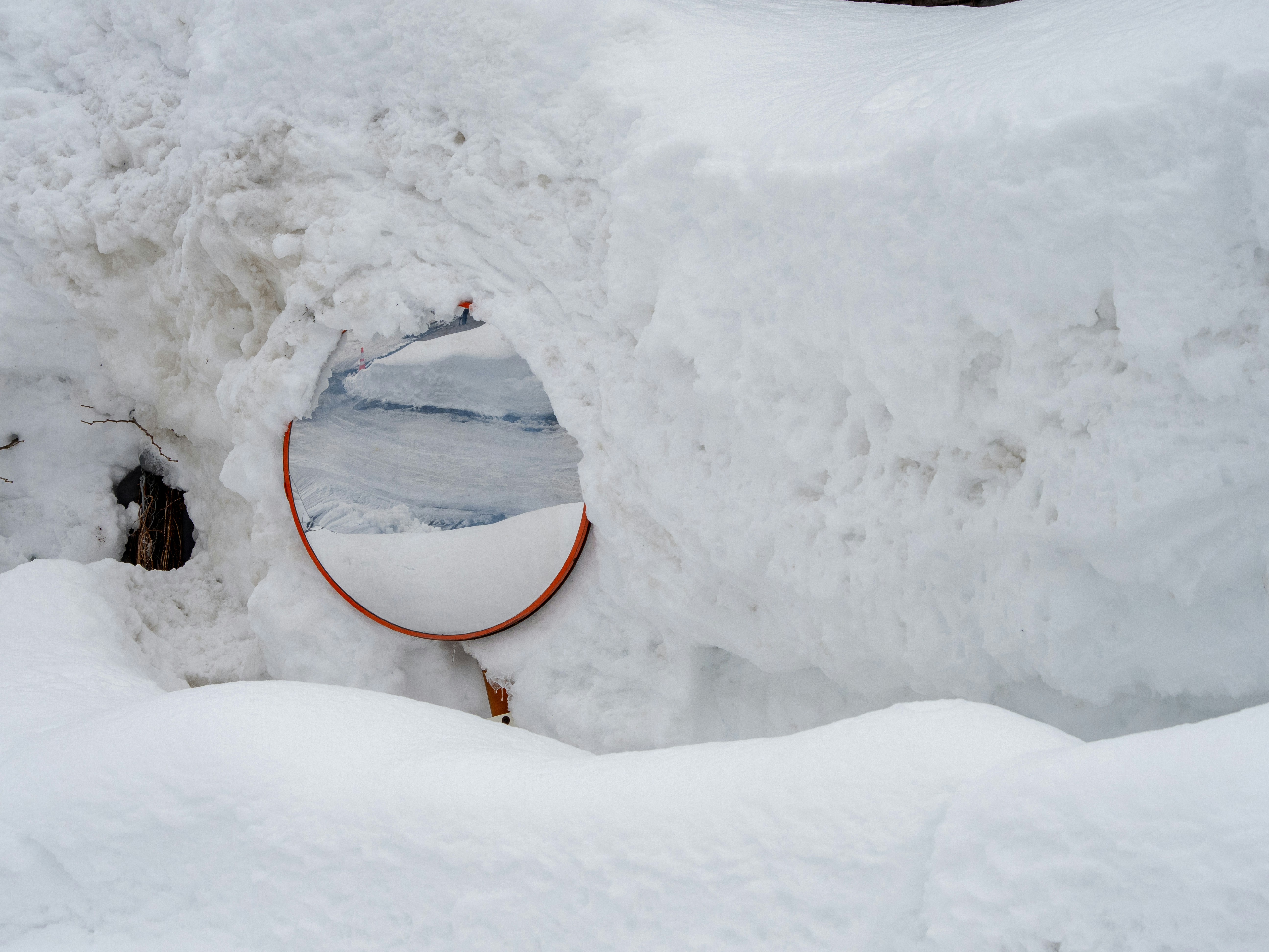 Red-Rimmed Snow Portal: A Circular Mirror Framed by Winter Drift