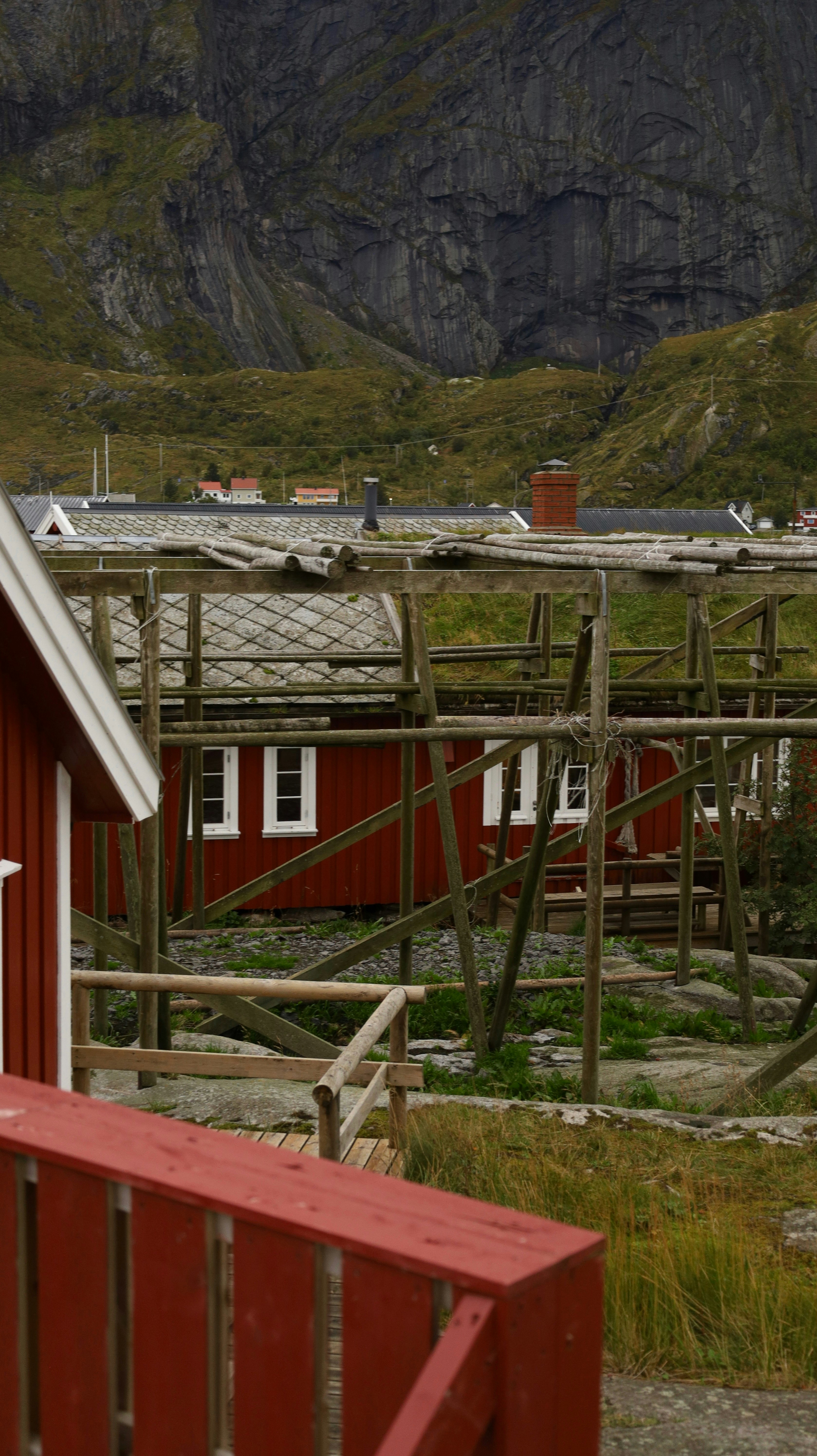 Red Cottages Framed by Weathered Scaffolding Beneath a Granite Mountain
