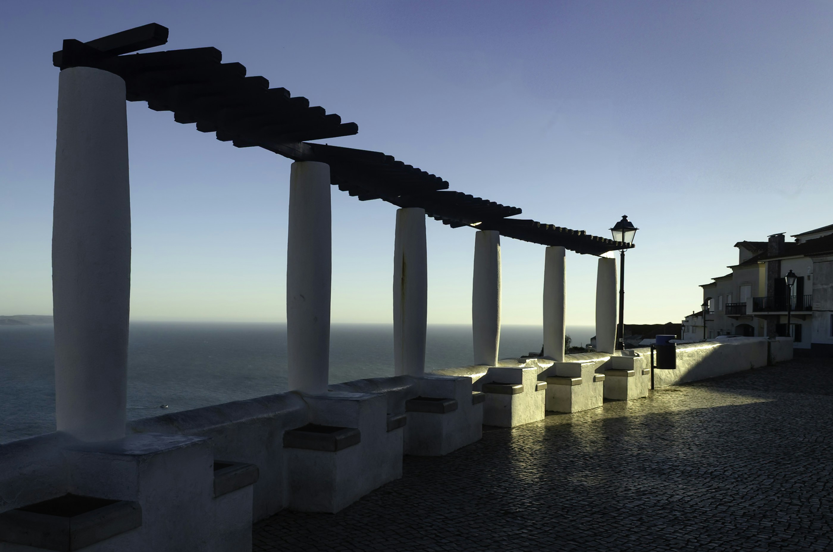 A row of white pillars sitting next to the ocean photo – Free City ...