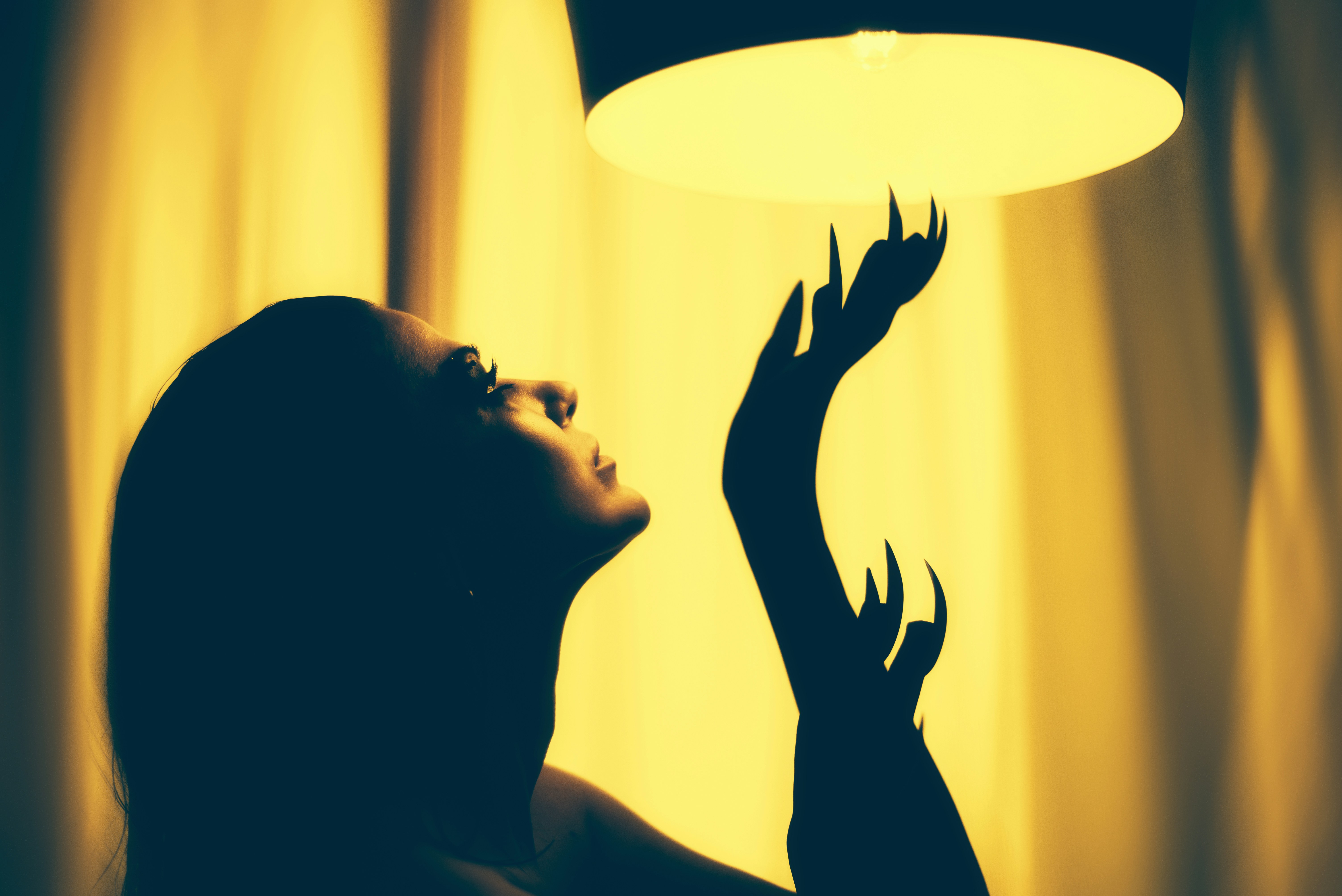 Warm Halo, Quiet Gesture: Silhouette Under a Pendant Light