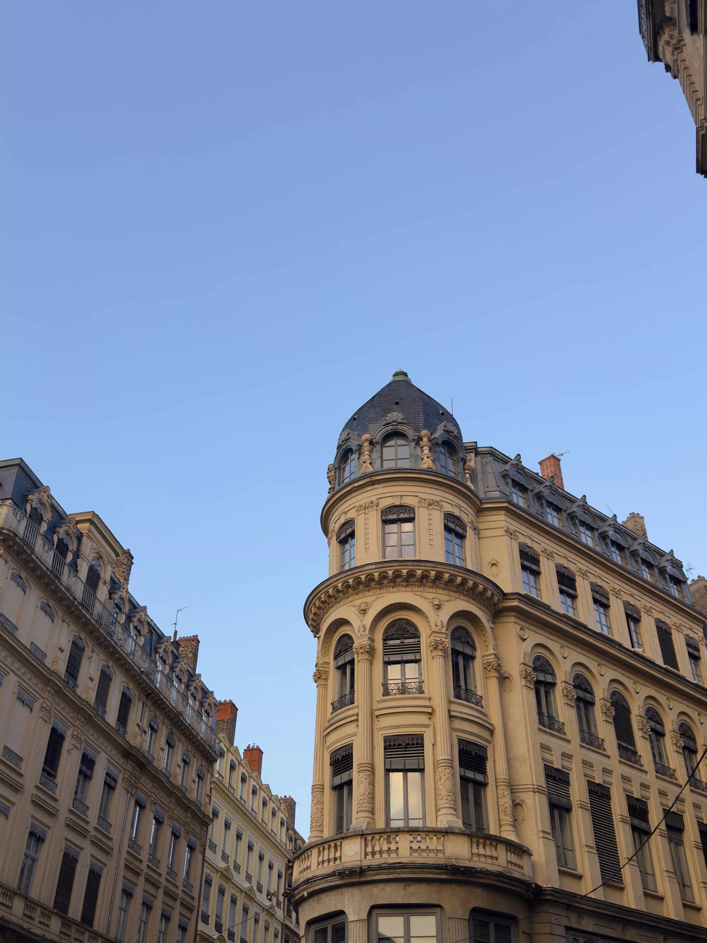 Ornate corner building with arched windows under a clear blue sky.