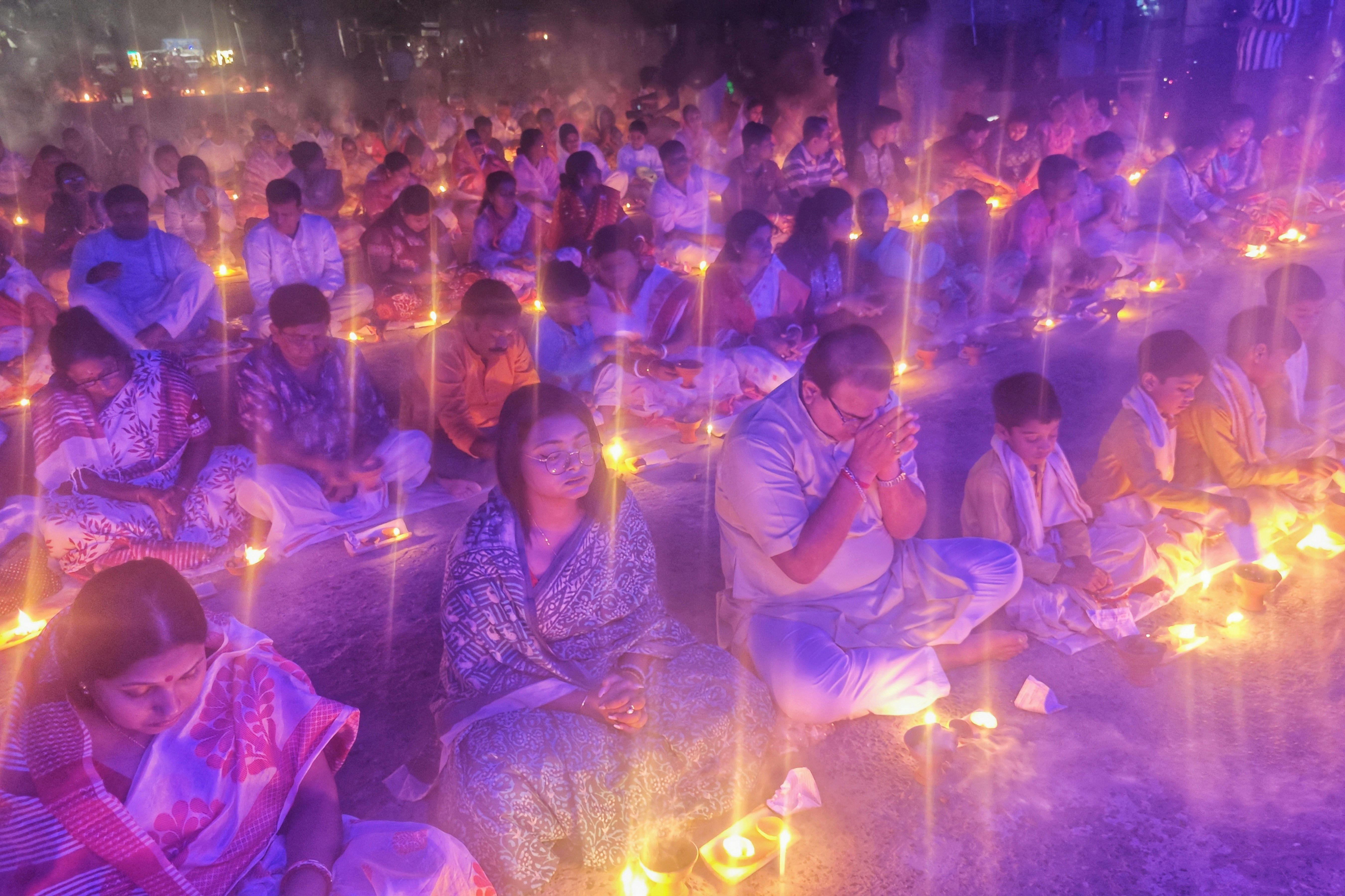People seated in a meditative gathering, surrounded by glowing candles in a serene atmosphere.