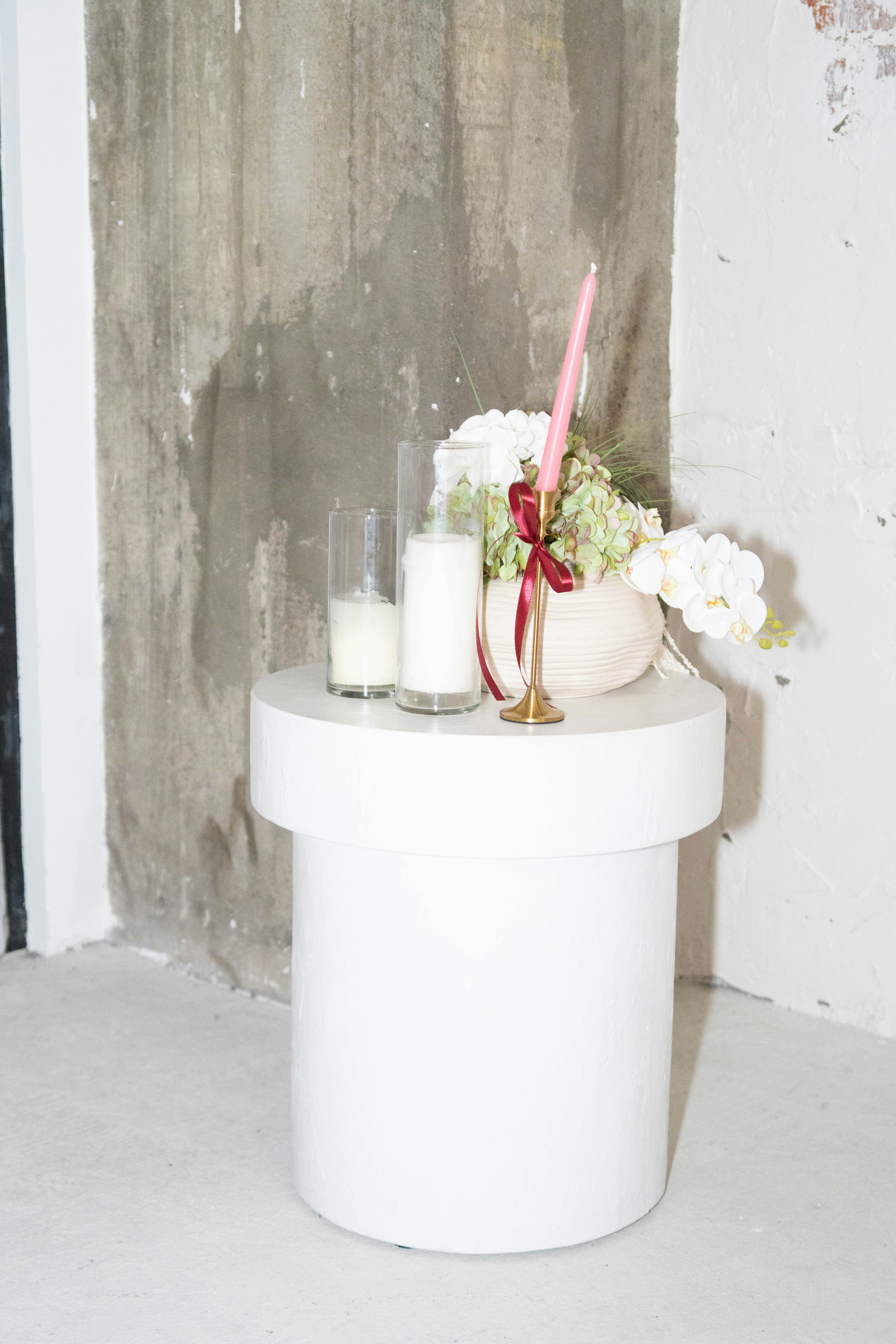 Ceremonial Pink Candle on a White Pedestal: A Quiet Still-Life with Florals