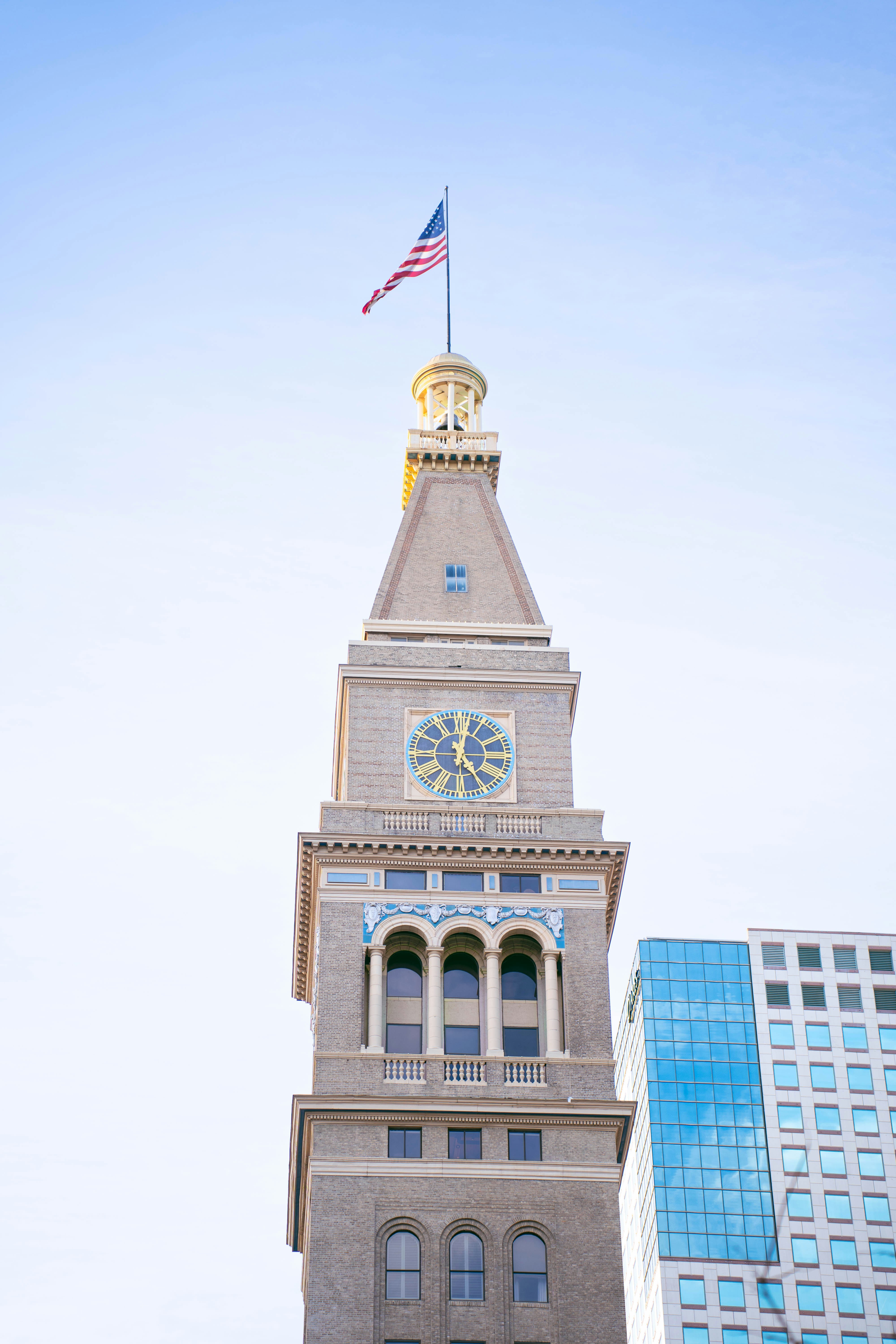 Historic clock tower with American flag atop, set against a clear blue sky.