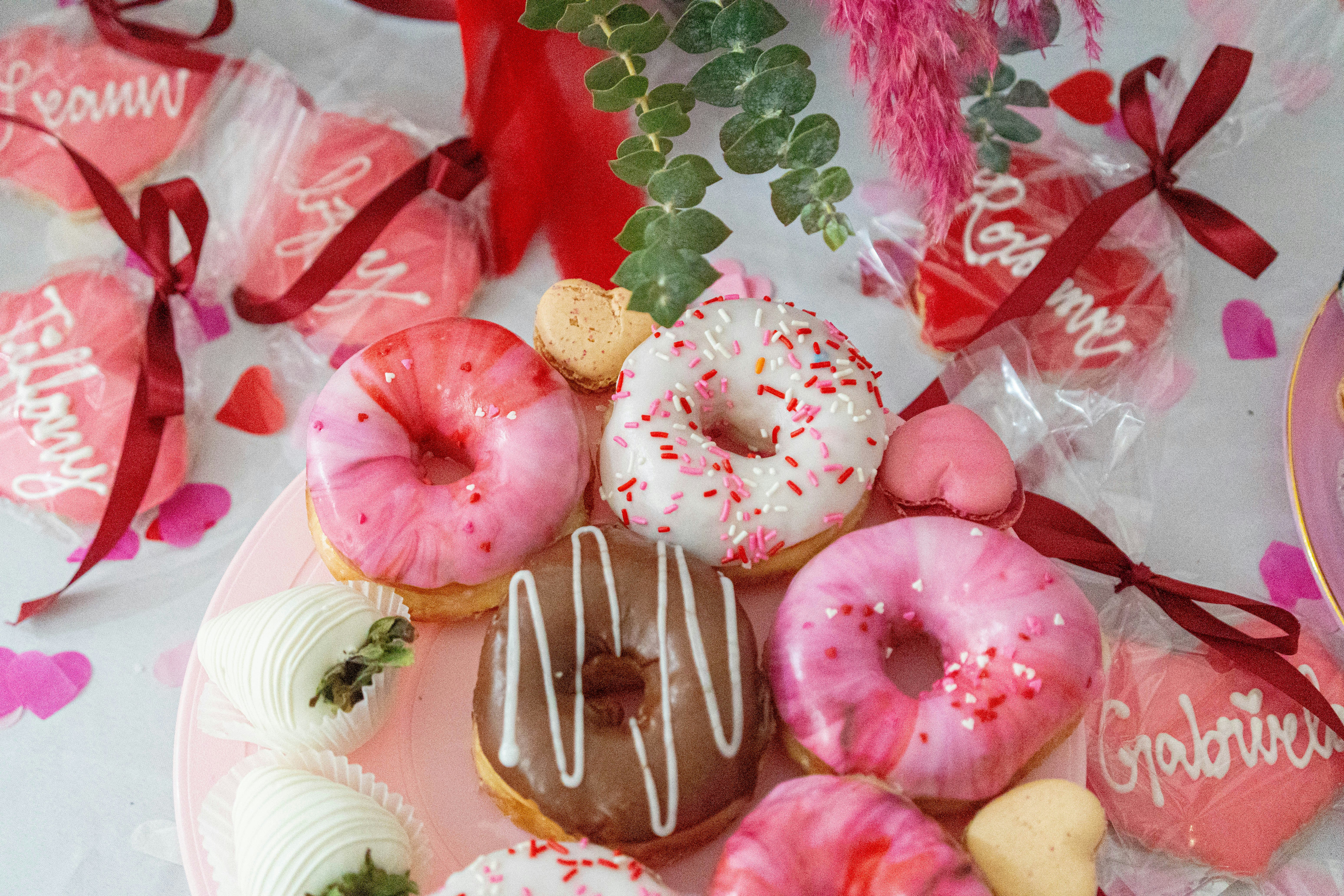 A pink plate topped with donuts covered in frosting