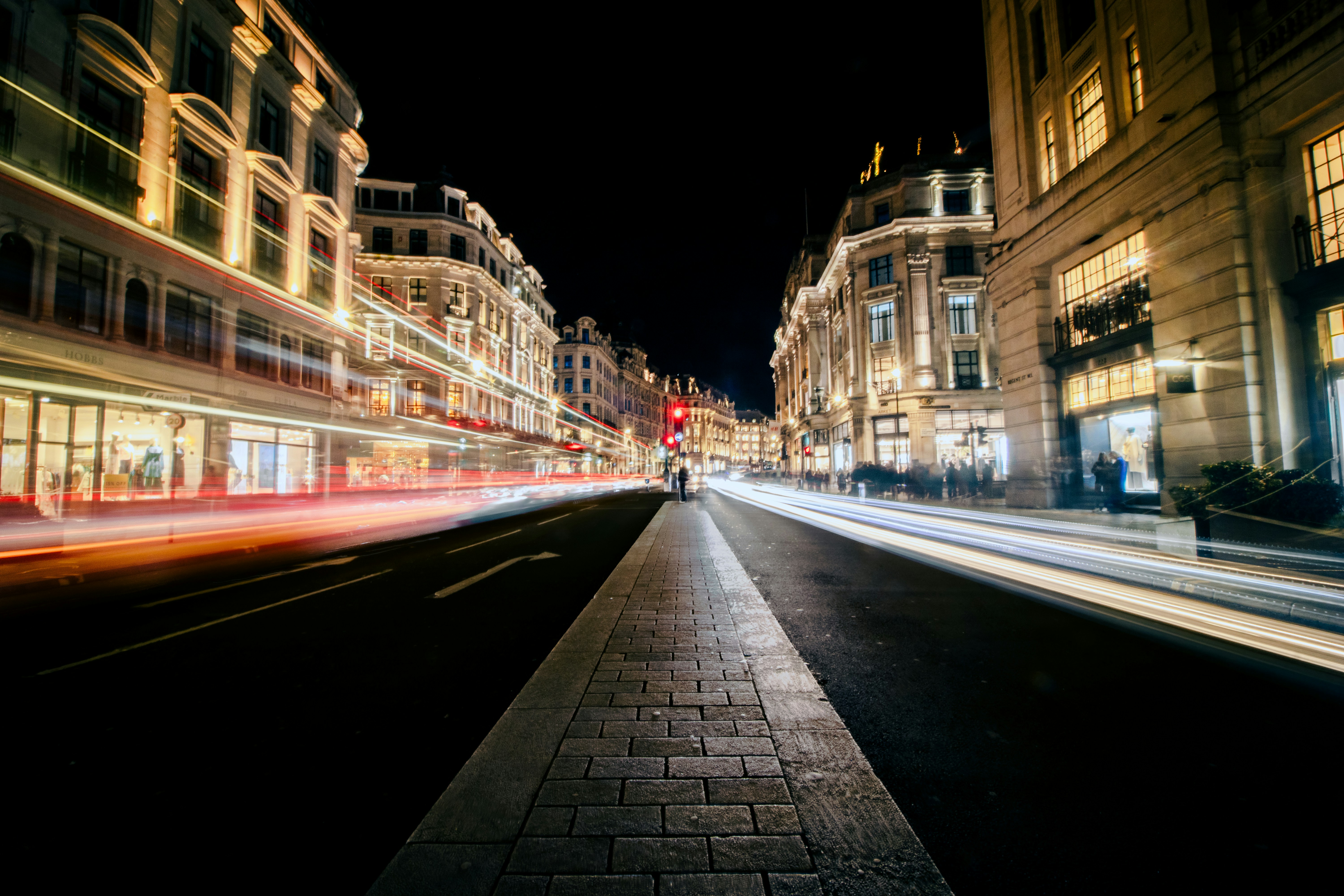 Long-exposure of Regent Street featuring vibrant light trails from vehicles against illuminated historic buildings.