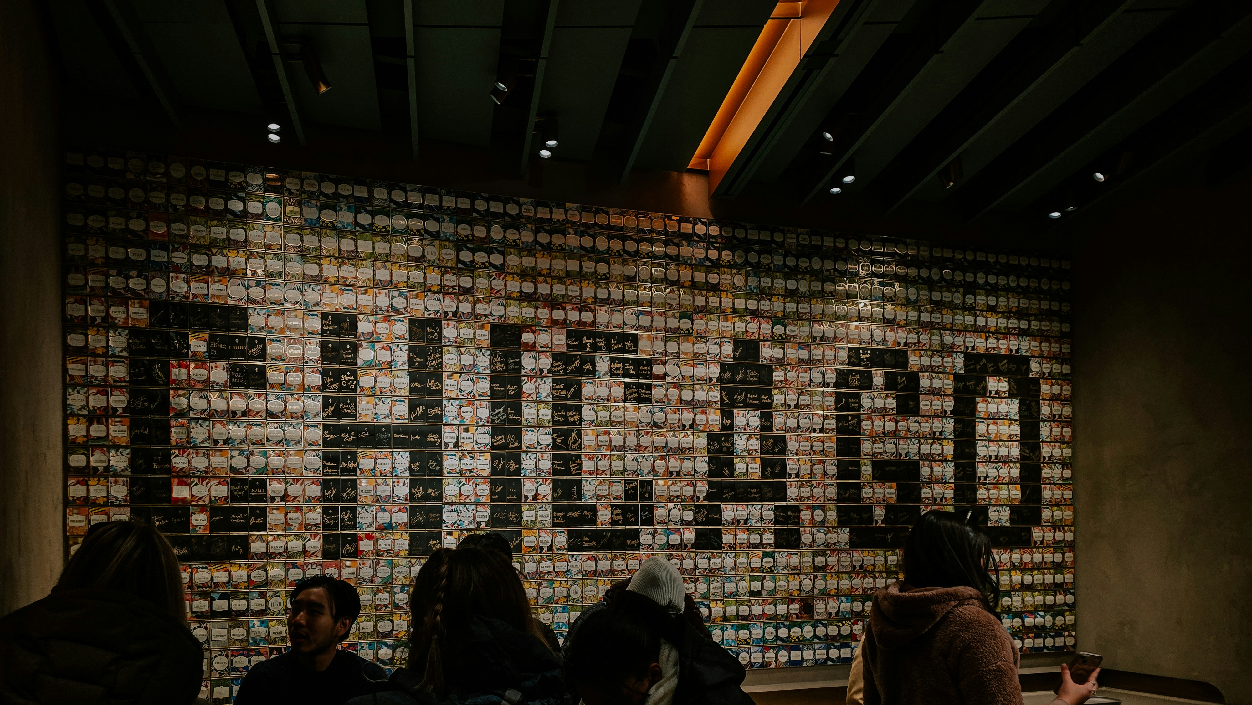 People gathered beneath a wall mosaic spelling 'Chicago' made of colorful tiles.