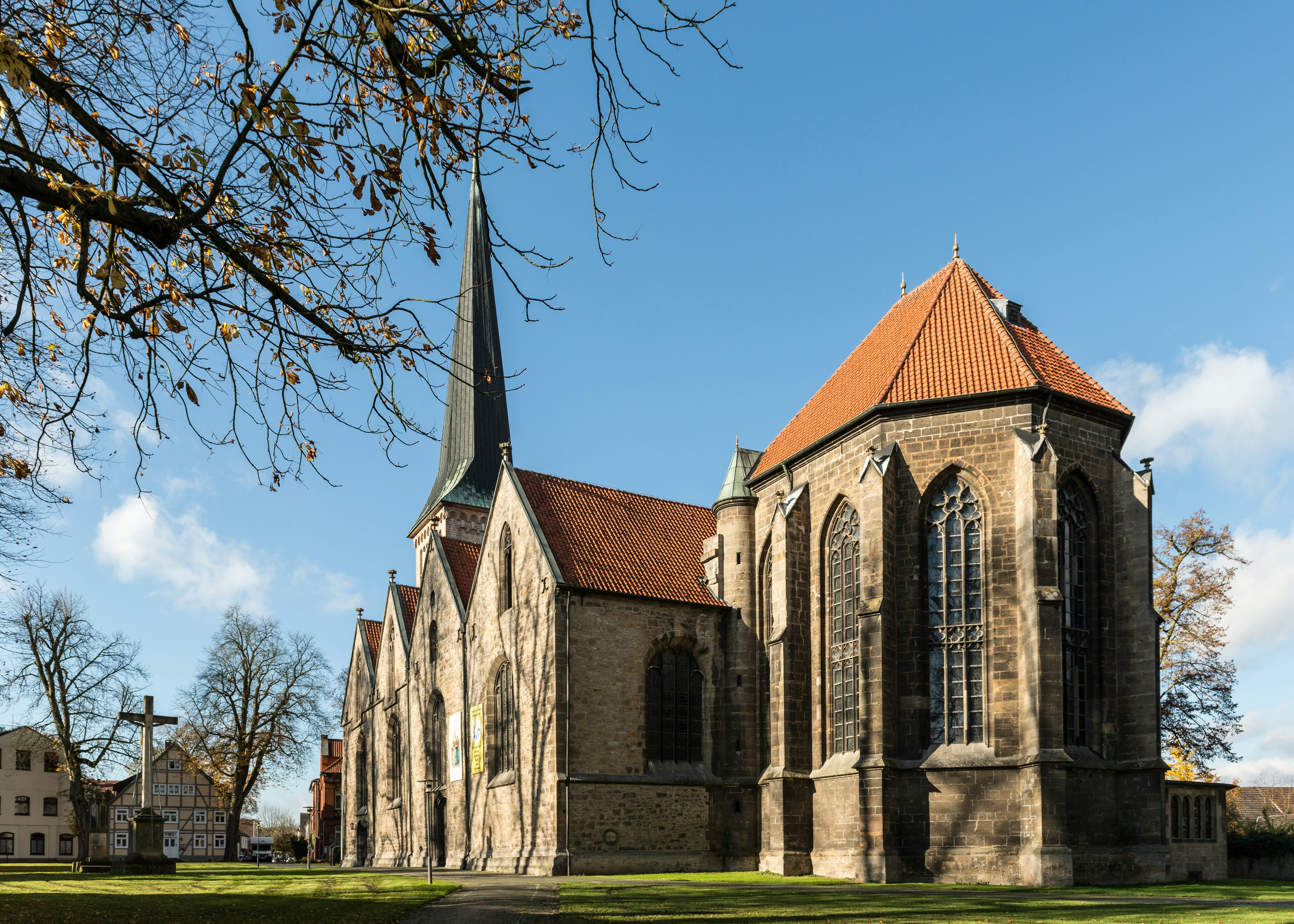 Historic church with Gothic architecture under a clear blue sky, framed by bare tree branches.