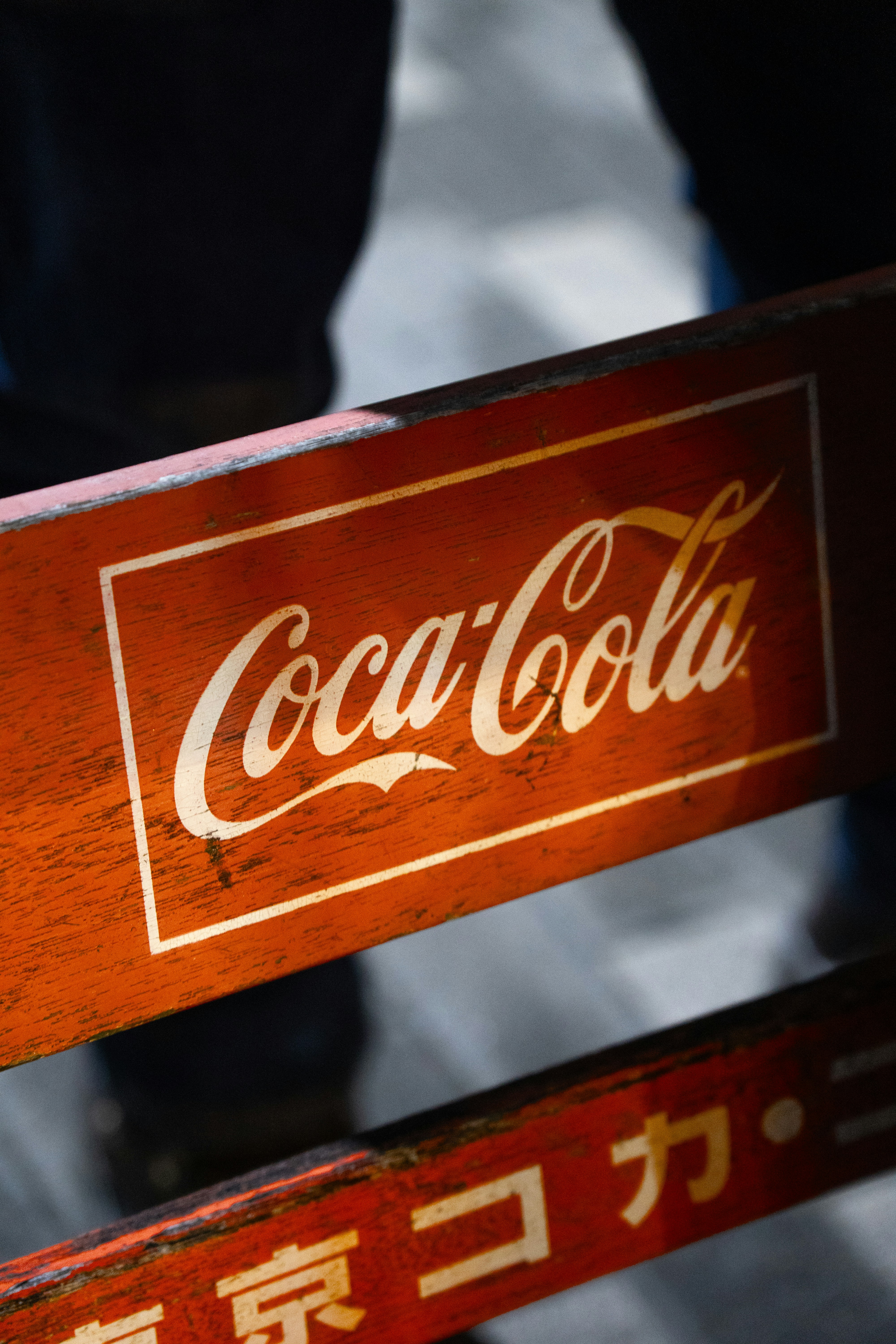 Coca-Cola Sign on Weathered Wood: Red Badge Amid Shadows