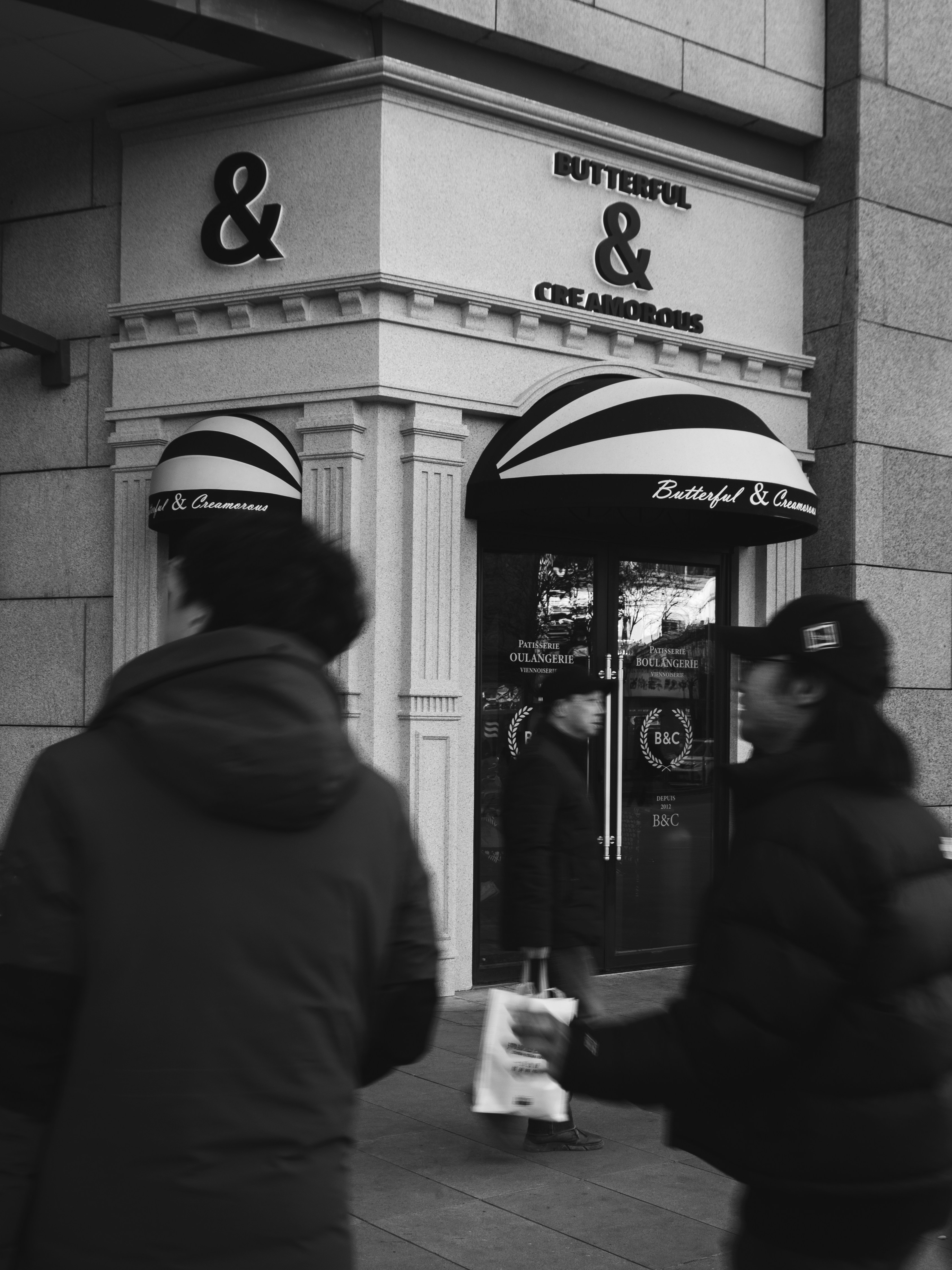 A black and white photo of two people standing outside of a store photo ...