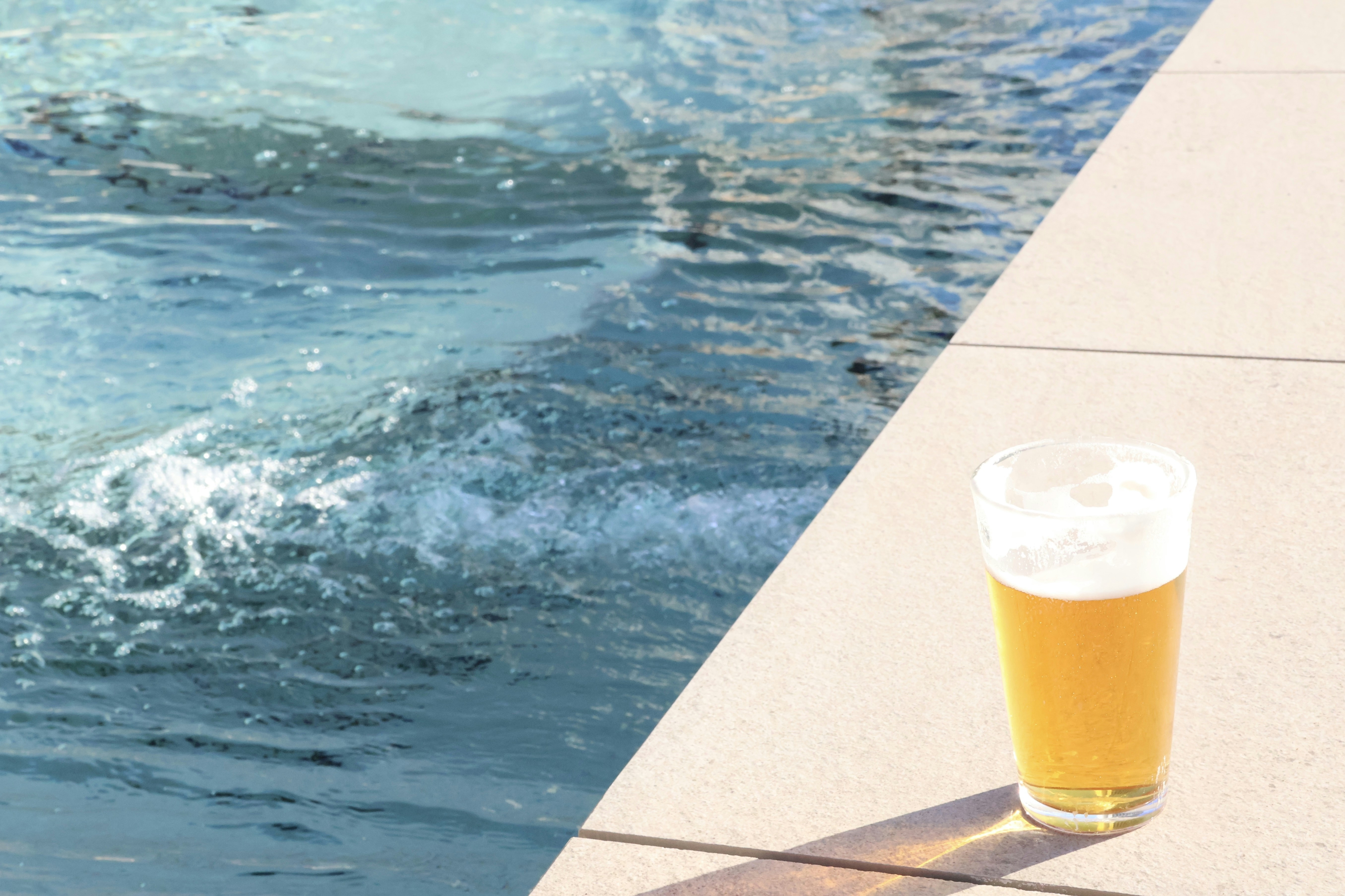 A glass of beer sitting next to a swimming pool photo – Free Beer Image ...