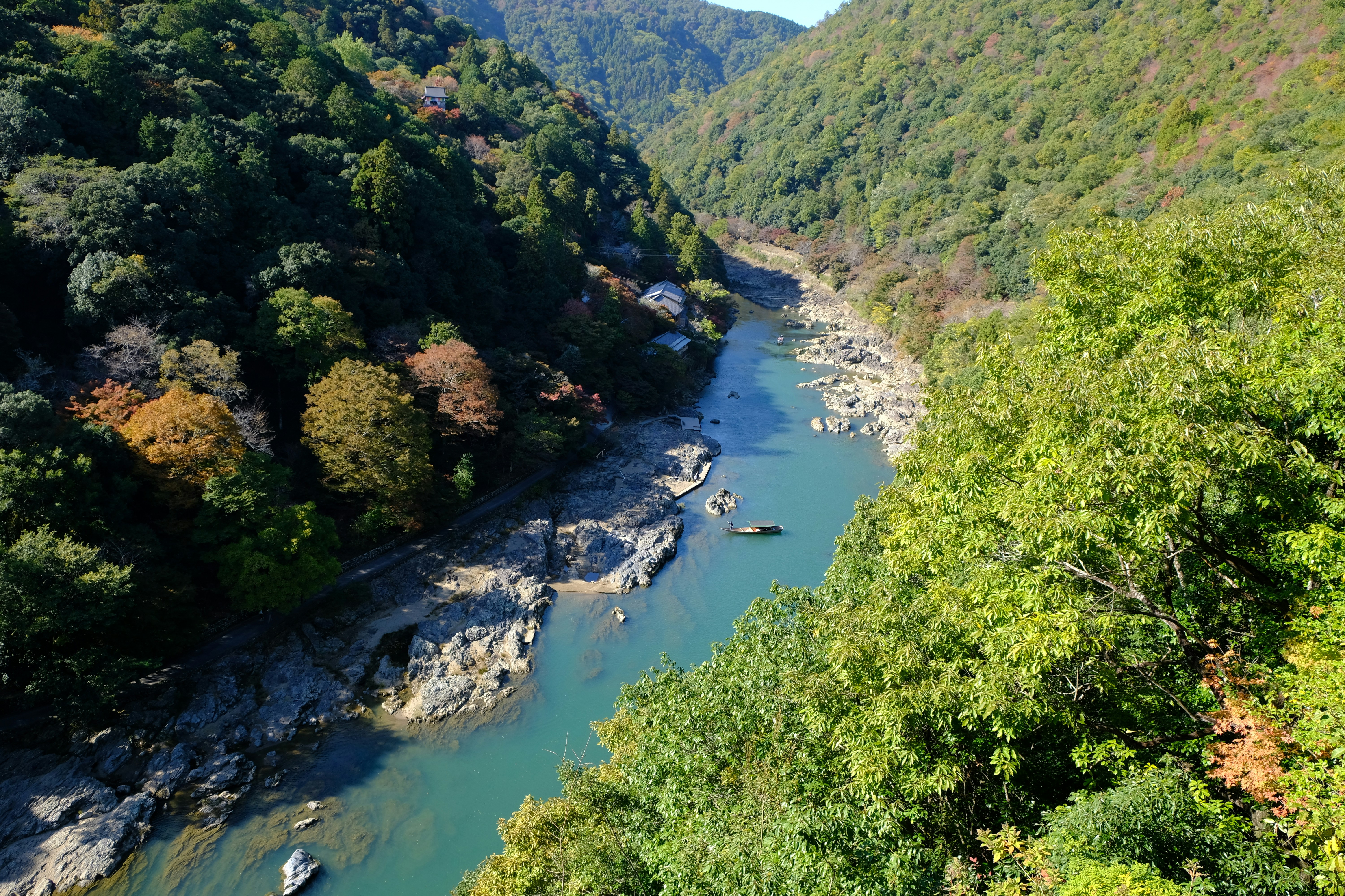 Winding river cuts through lush, tree-covered hills under a clear sky.