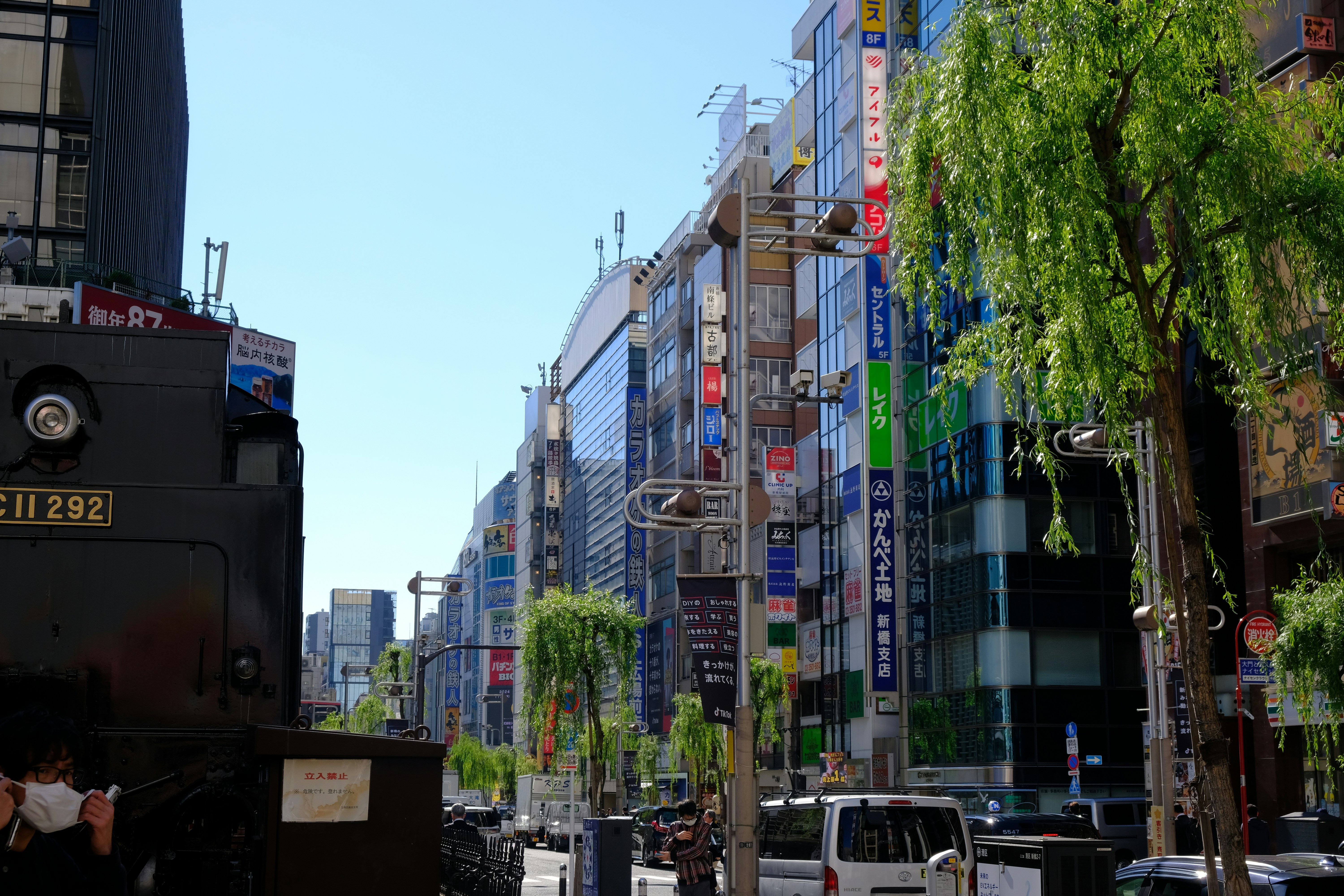 Neon Artery: Sunlit Tokyo-Style Street Framed by Glass Towers