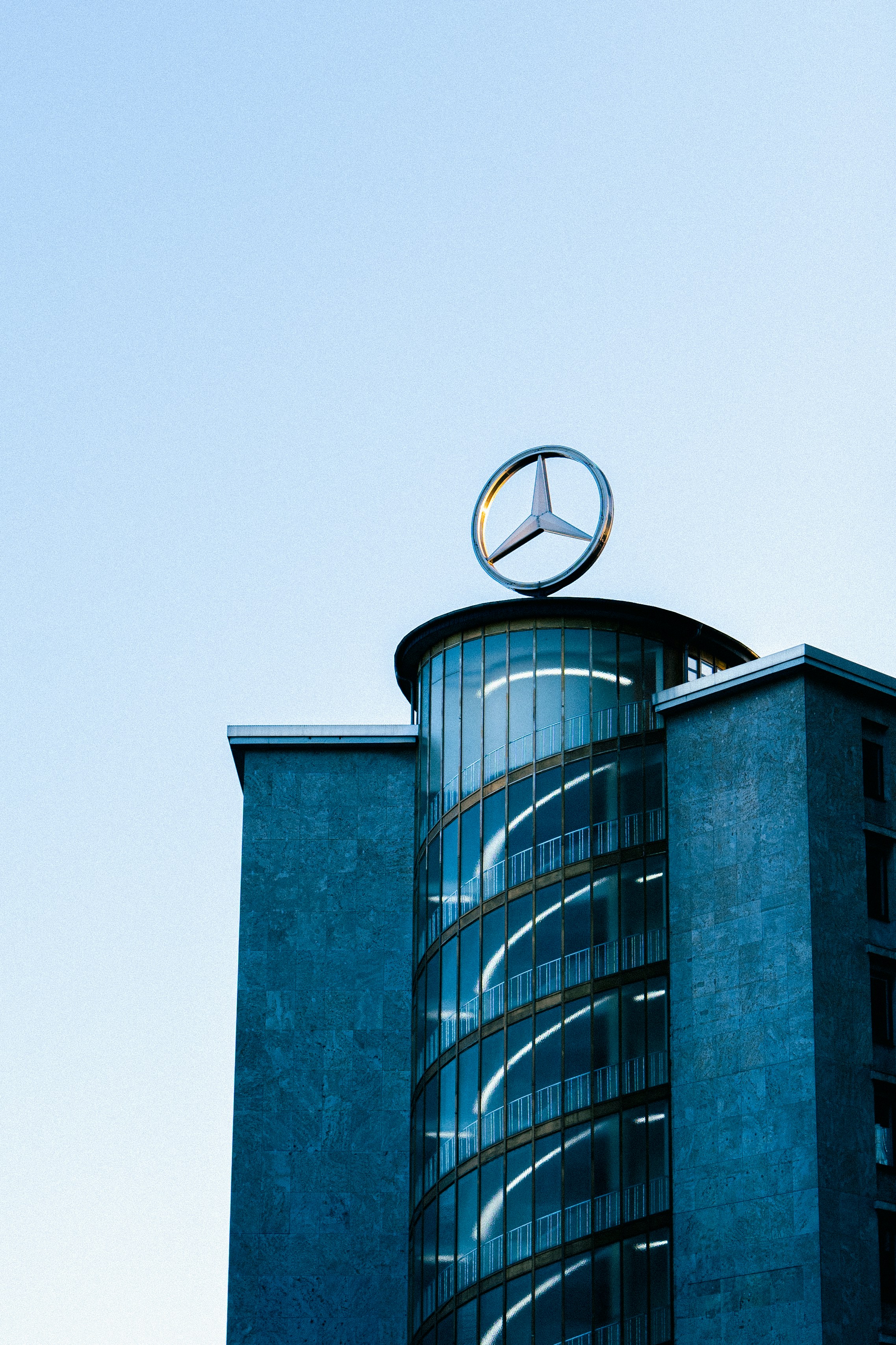 A Sky-Top Emblem: Mercedes-Benz Crown Above the Modern Glass Cylinder
