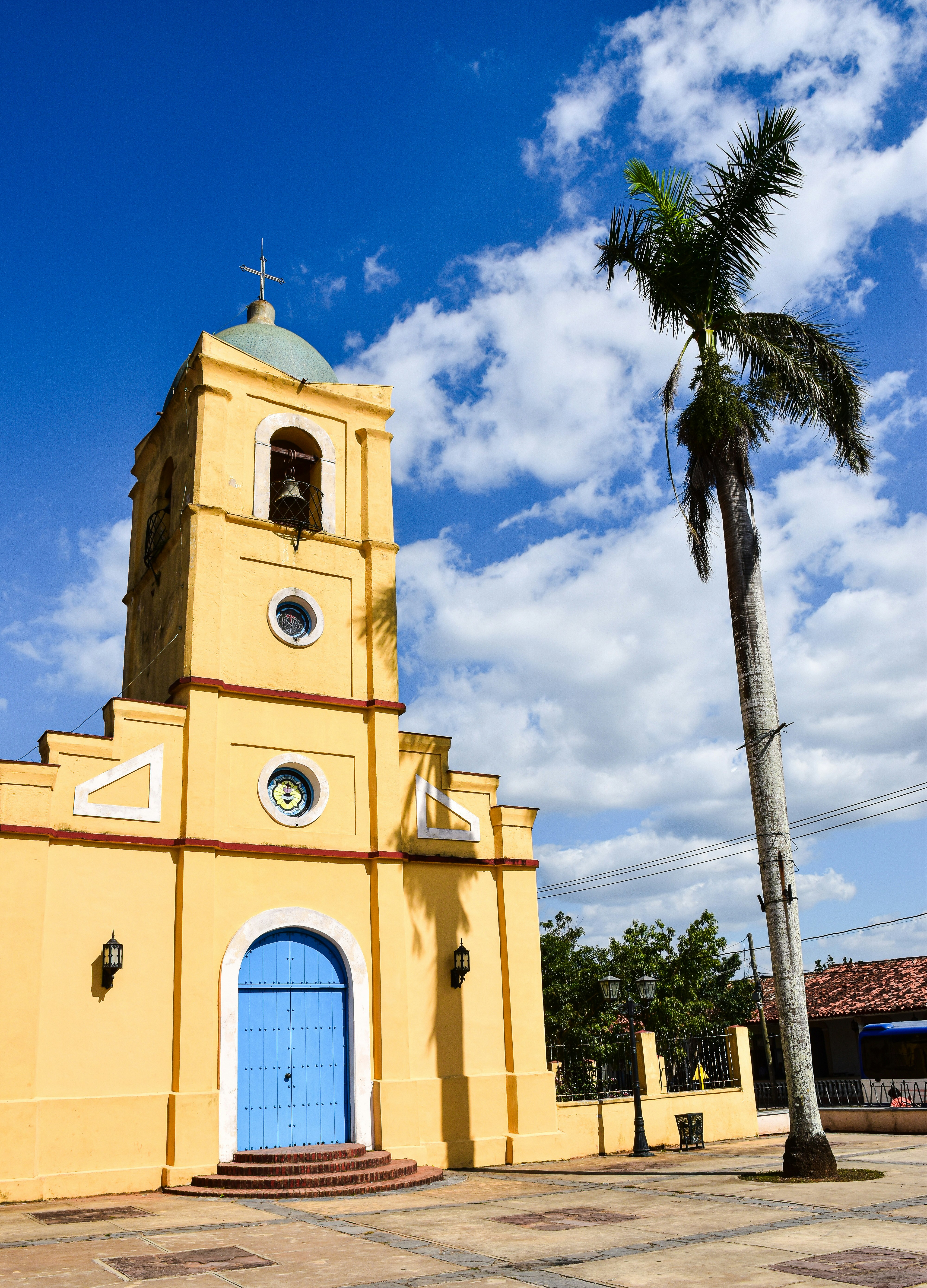 A yellow church with a blue door and a palm tree photo – Free Travel ...