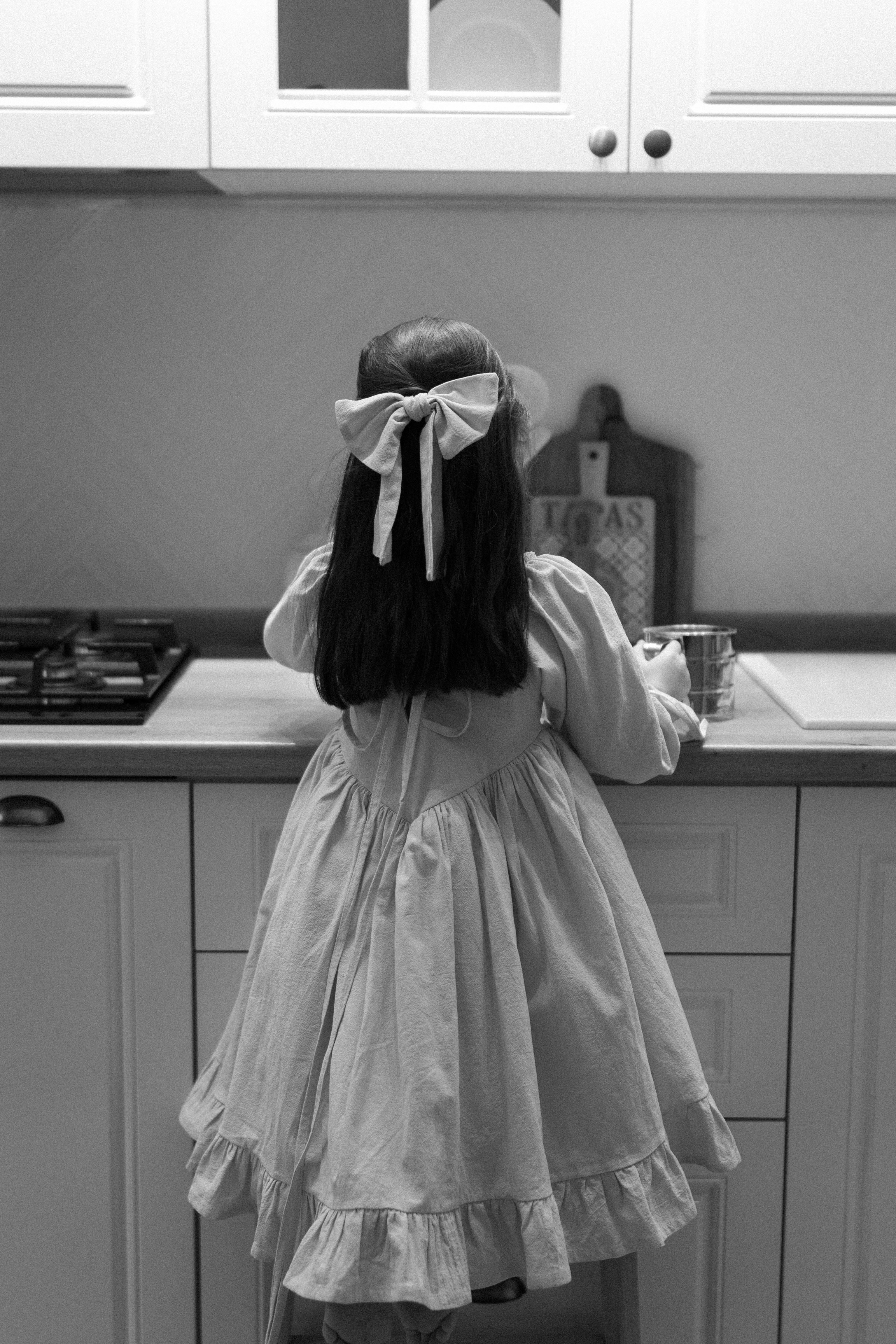 Shadowed Whimsy: A Little Girl at the Kitchen Counter