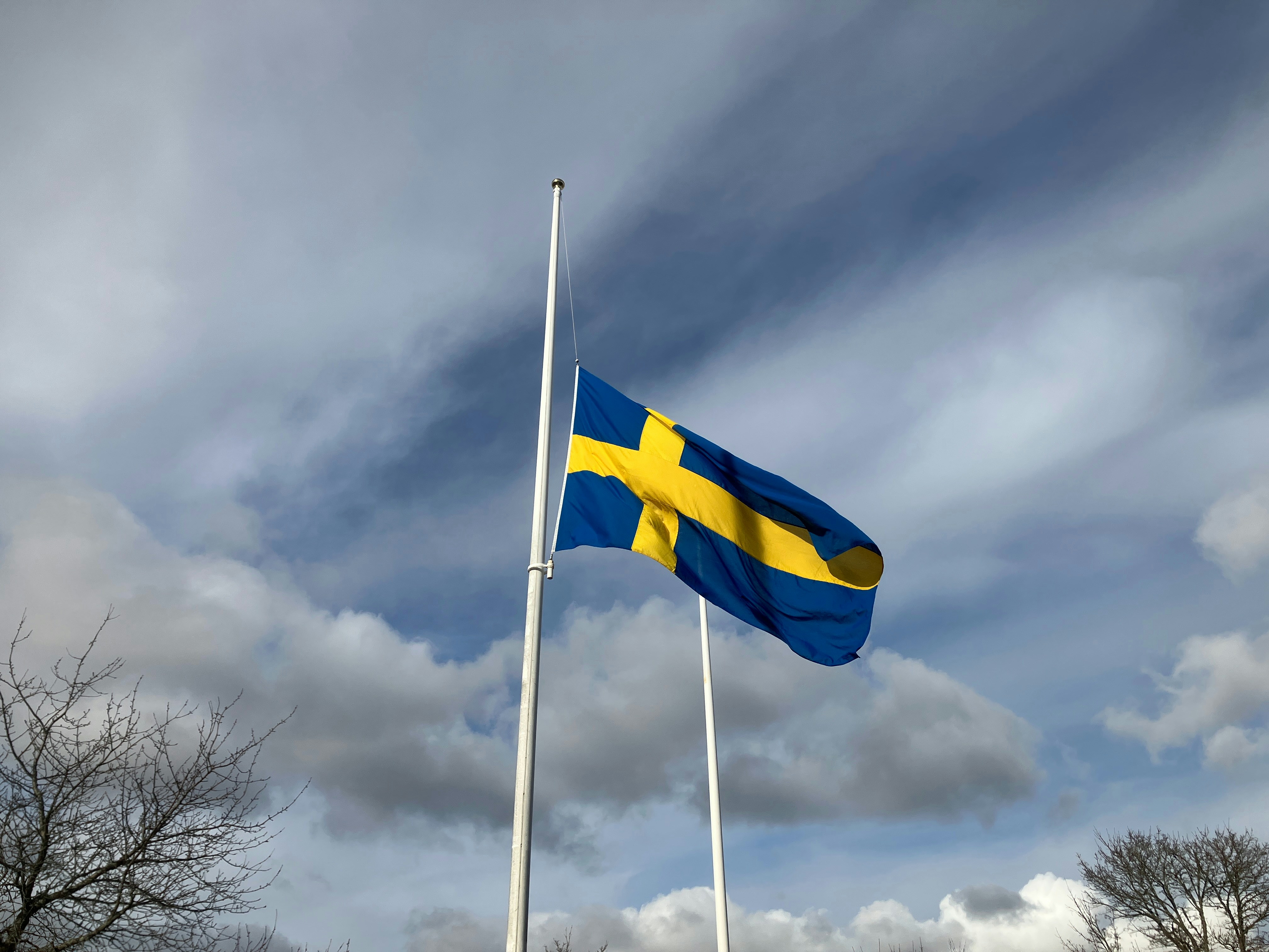 A flag that is halfways up | A flag flying in the wind on a cloudy day