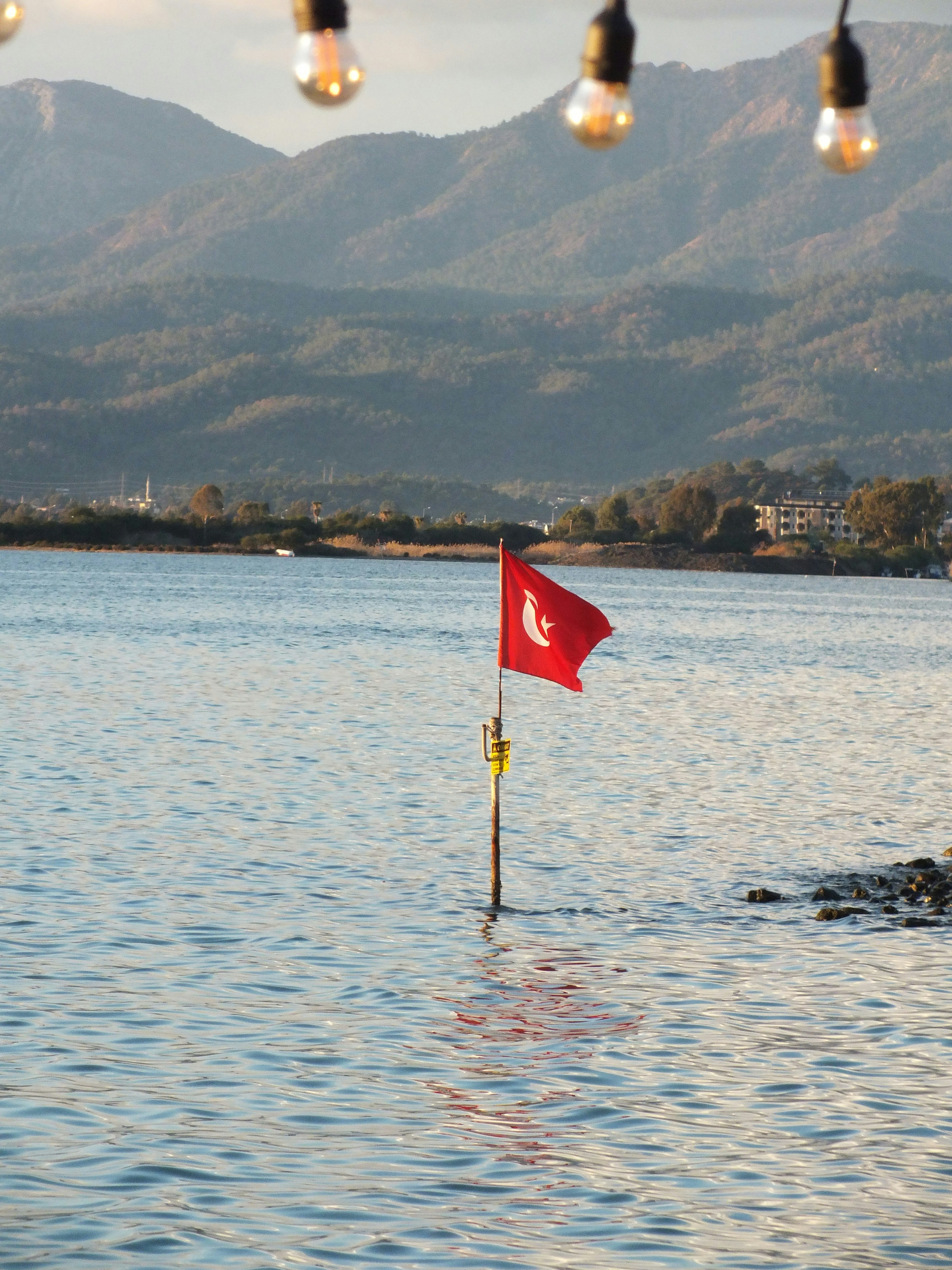 A red flag on a pole in the middle of a body of water photo – Free Flag ...