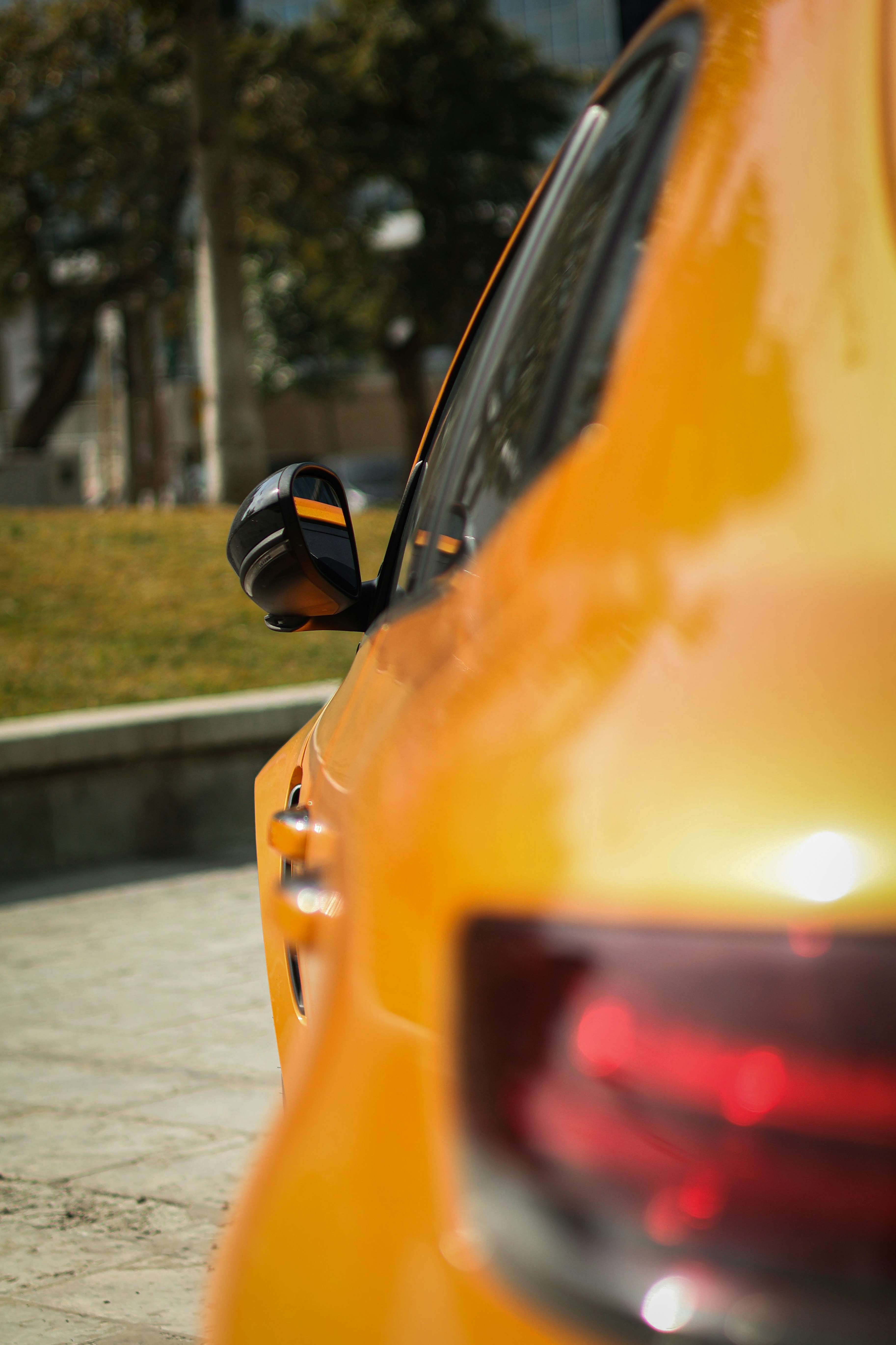 Orange car door sculpture: a close-up of side mirror and body curvature