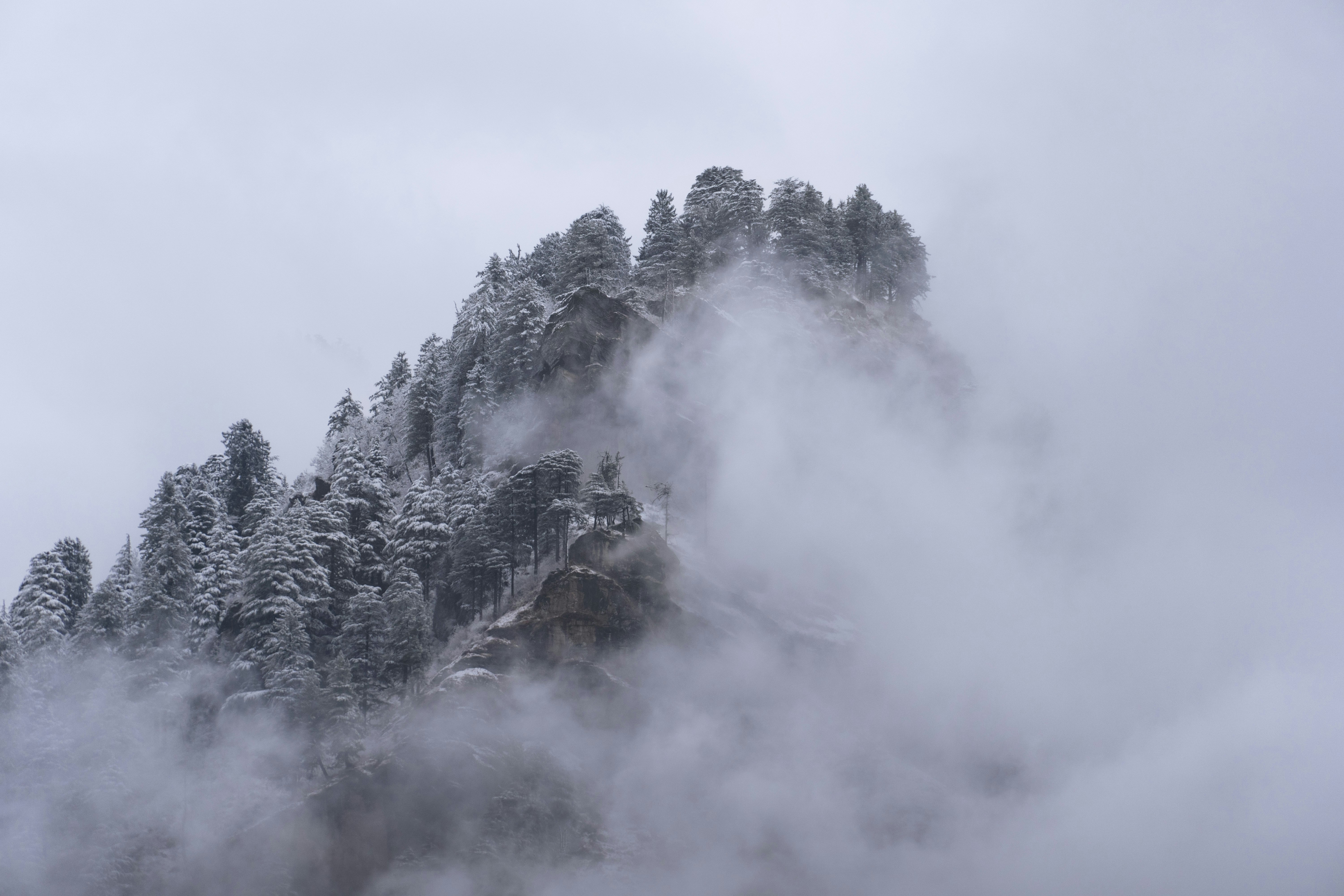 A mountain covered in snow and fog on a cloudy day