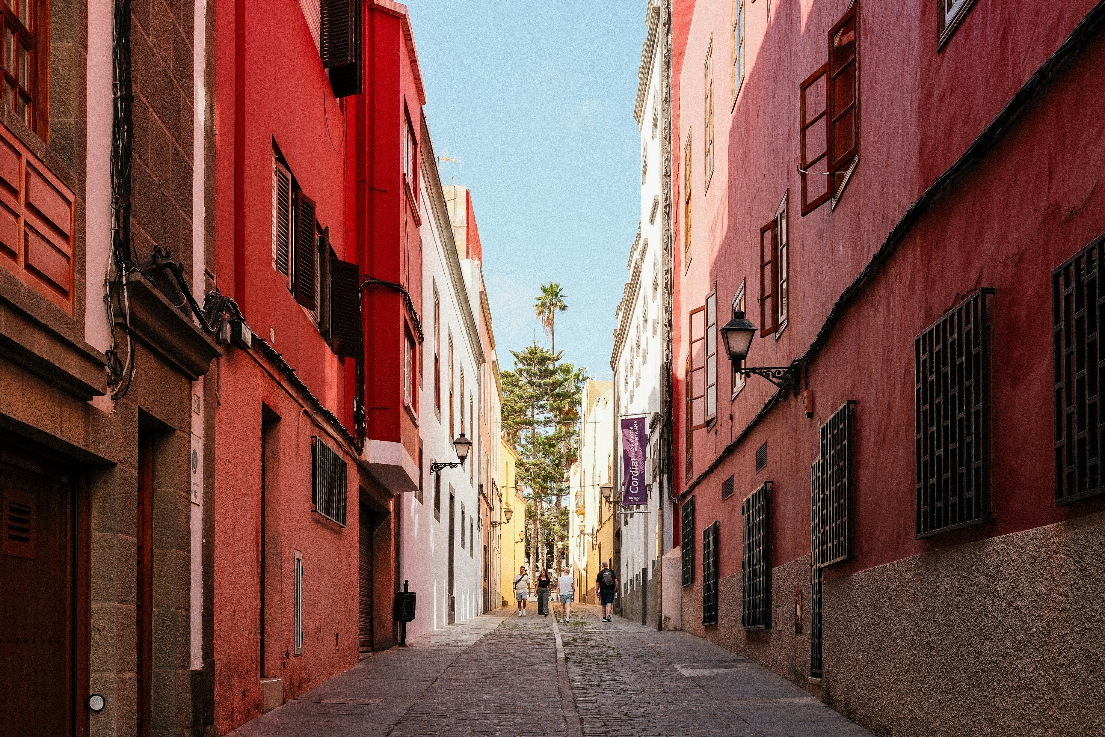 Narrow cobblestone street with colorful buildings and a clear blue sky.