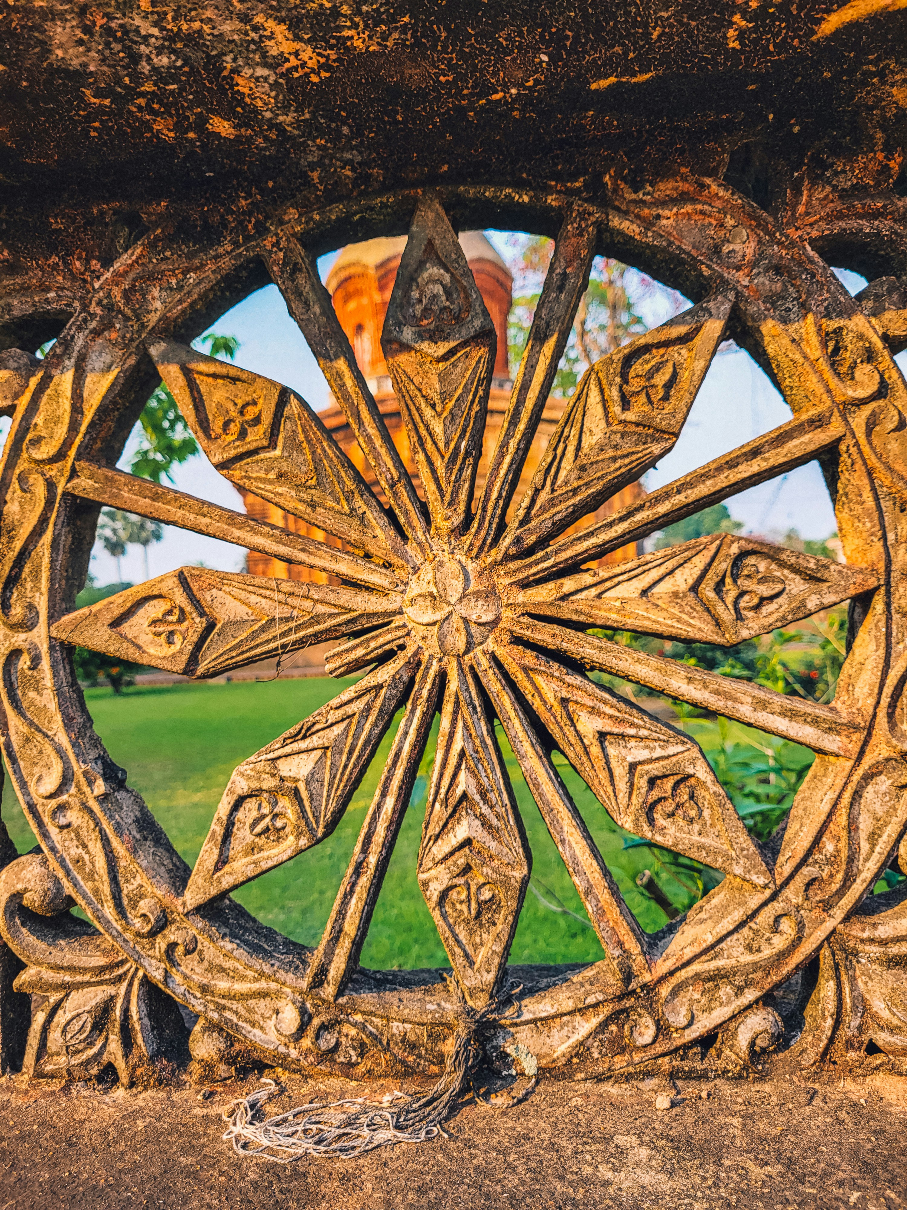Sunburst Ironwork: A rusted circular wheel framing a sunlit garden