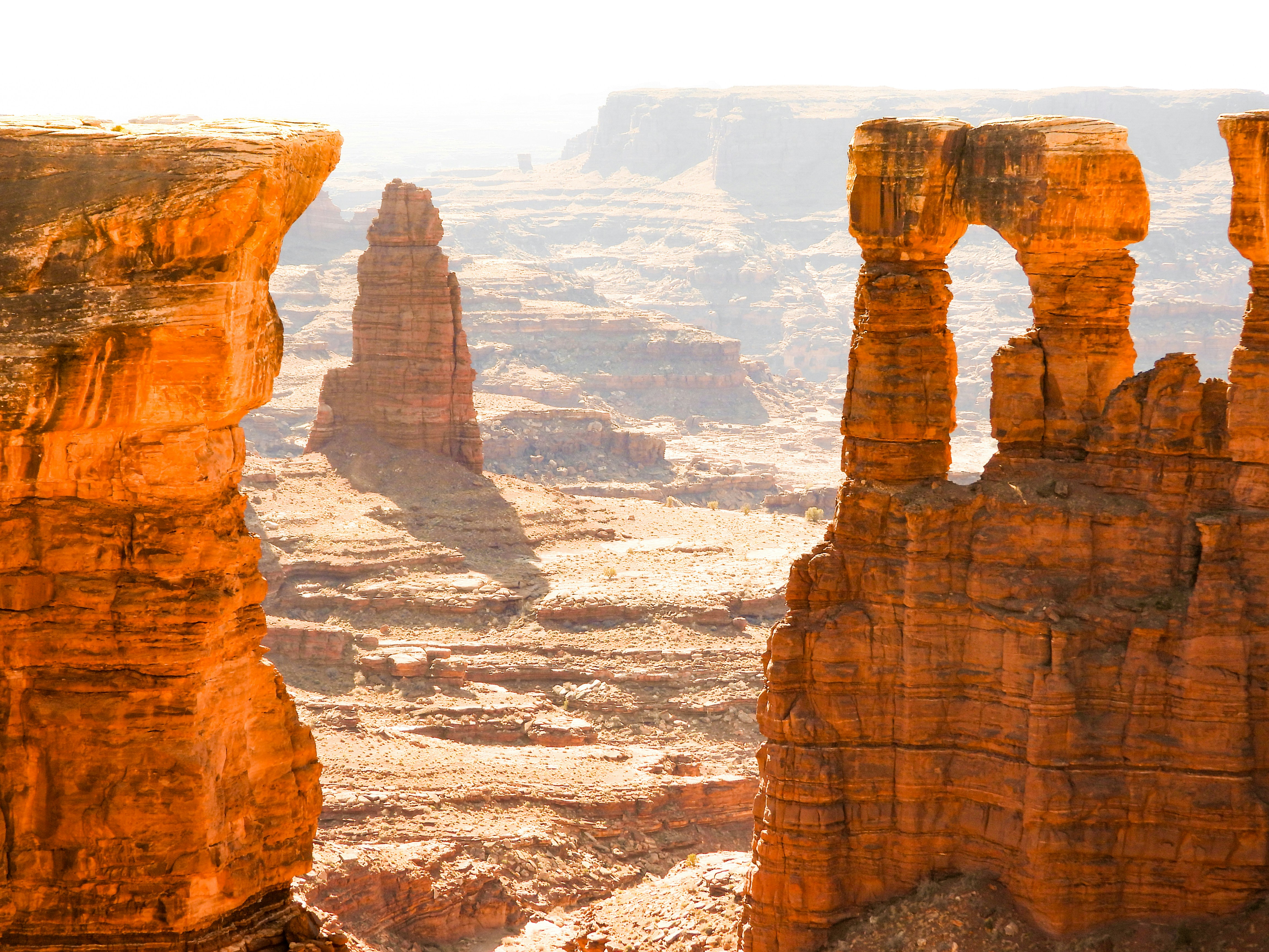 Natural rock formations bathed in warm sunlight, casting shadows across a vast canyon landscape.