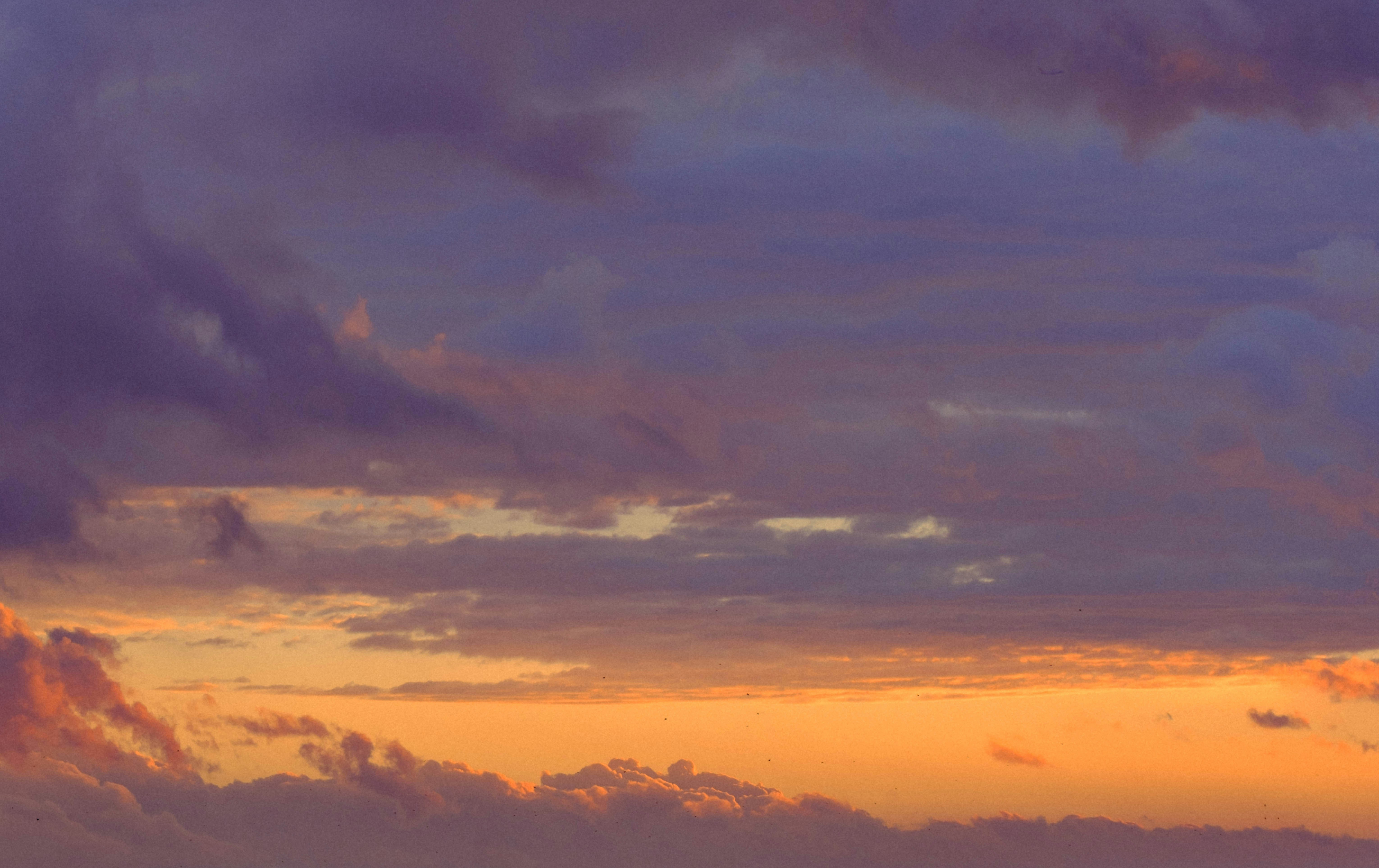 Vibrant sunset sky with layers of orange, purple, and gray clouds.