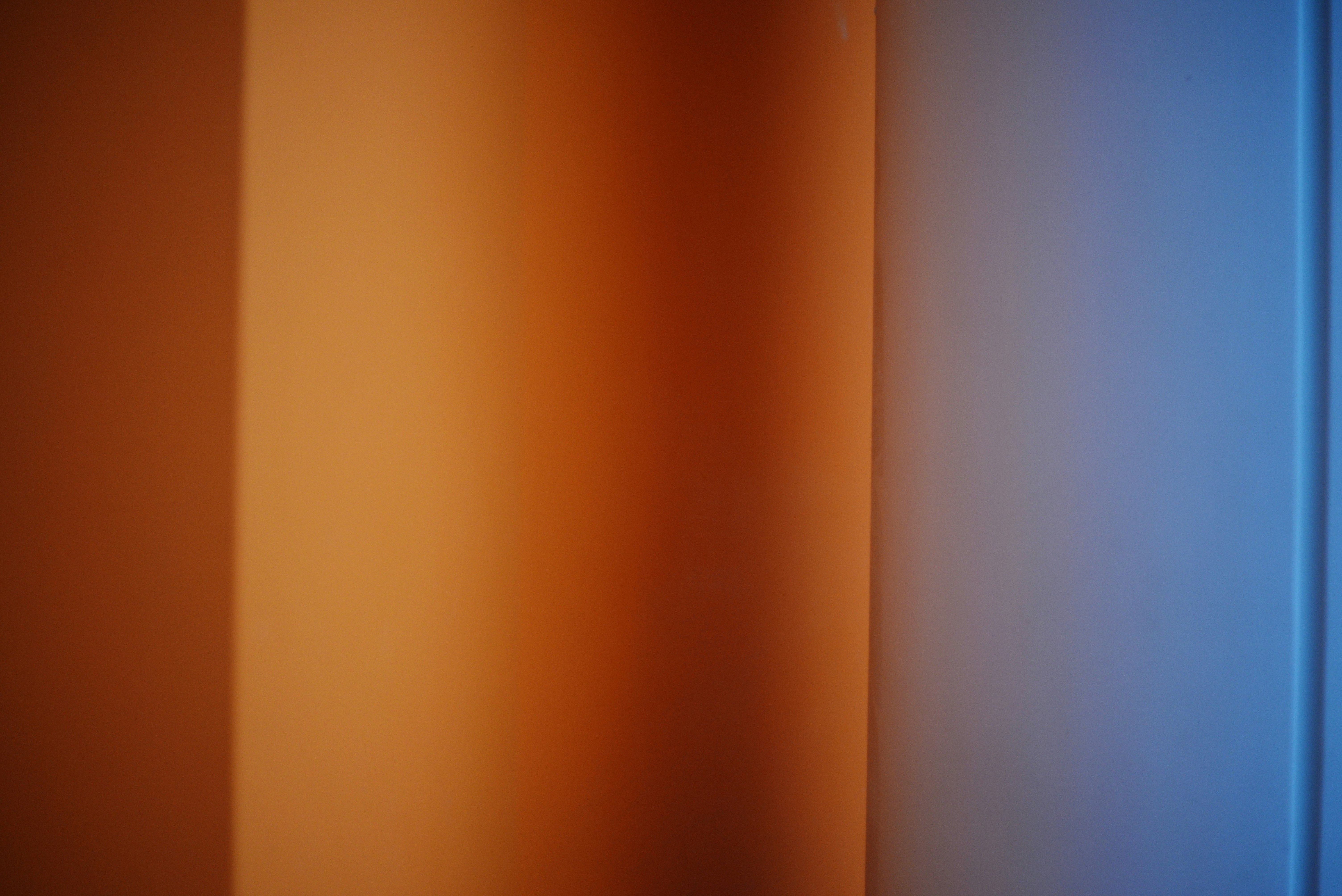 A seamless blend of warm orange and cool blue hues creating a striking visual contrast between two walls.