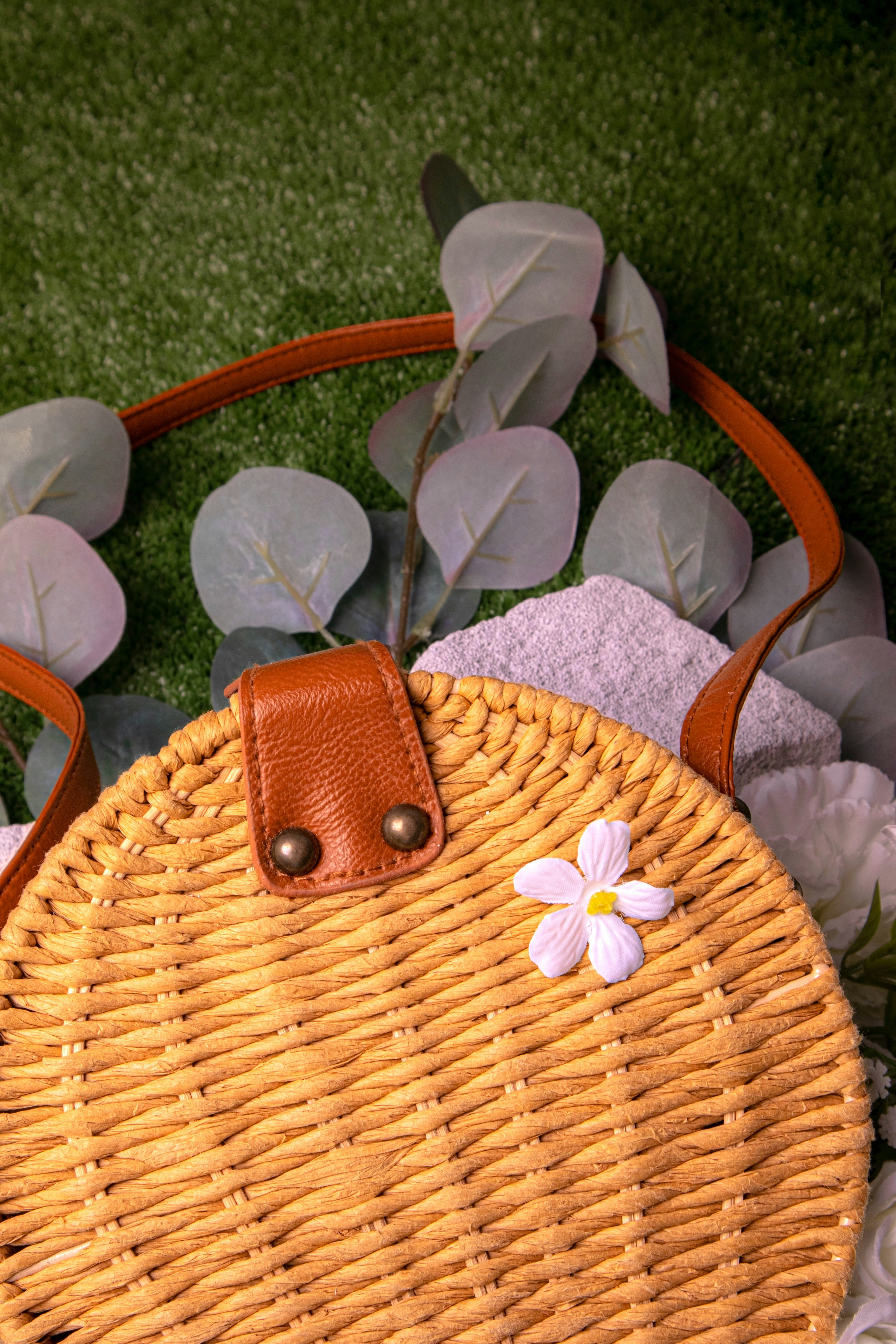 Woven Spotlight: A Round Straw Bag Adorned with a Delicate Pink Flower