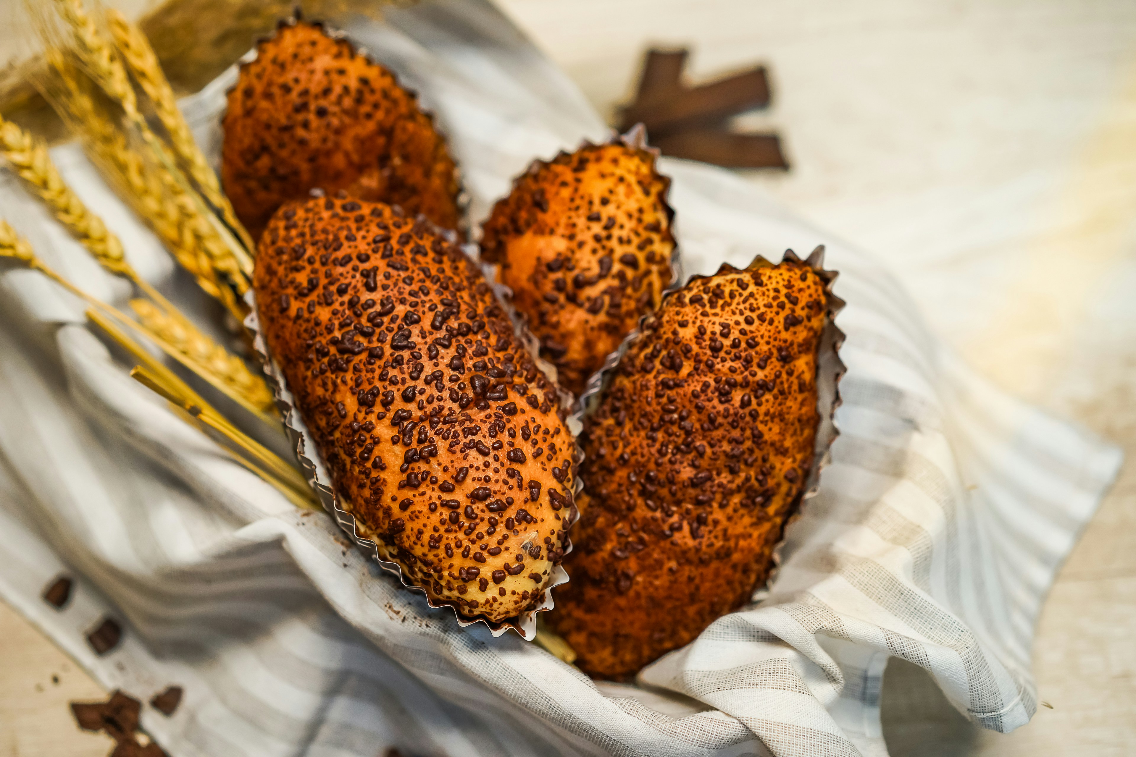Golden brown pastries with chocolate sprinkles in a striped cloth-lined basket.