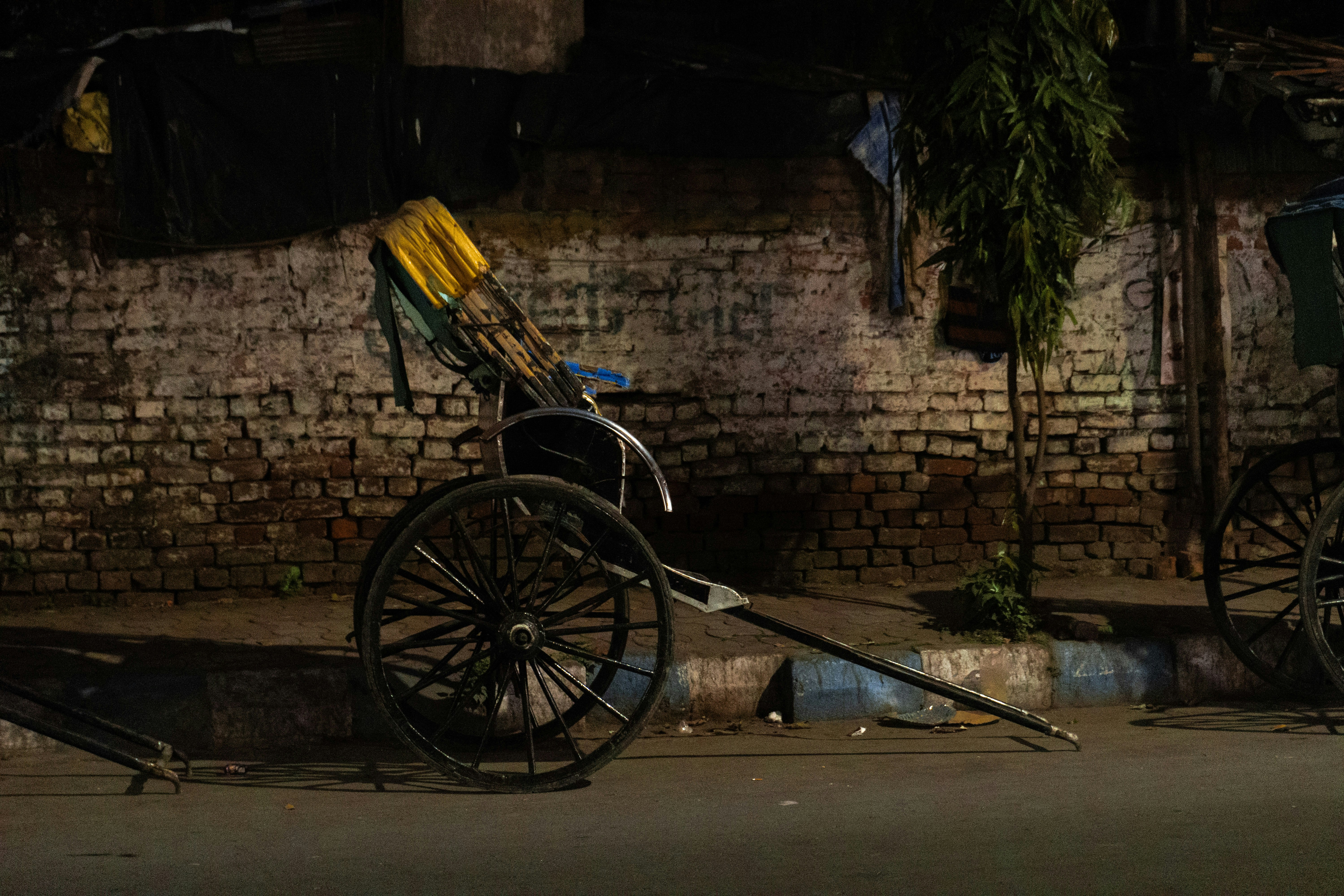 A rickshaw sitting on the side of a road at night photo – Free City ...