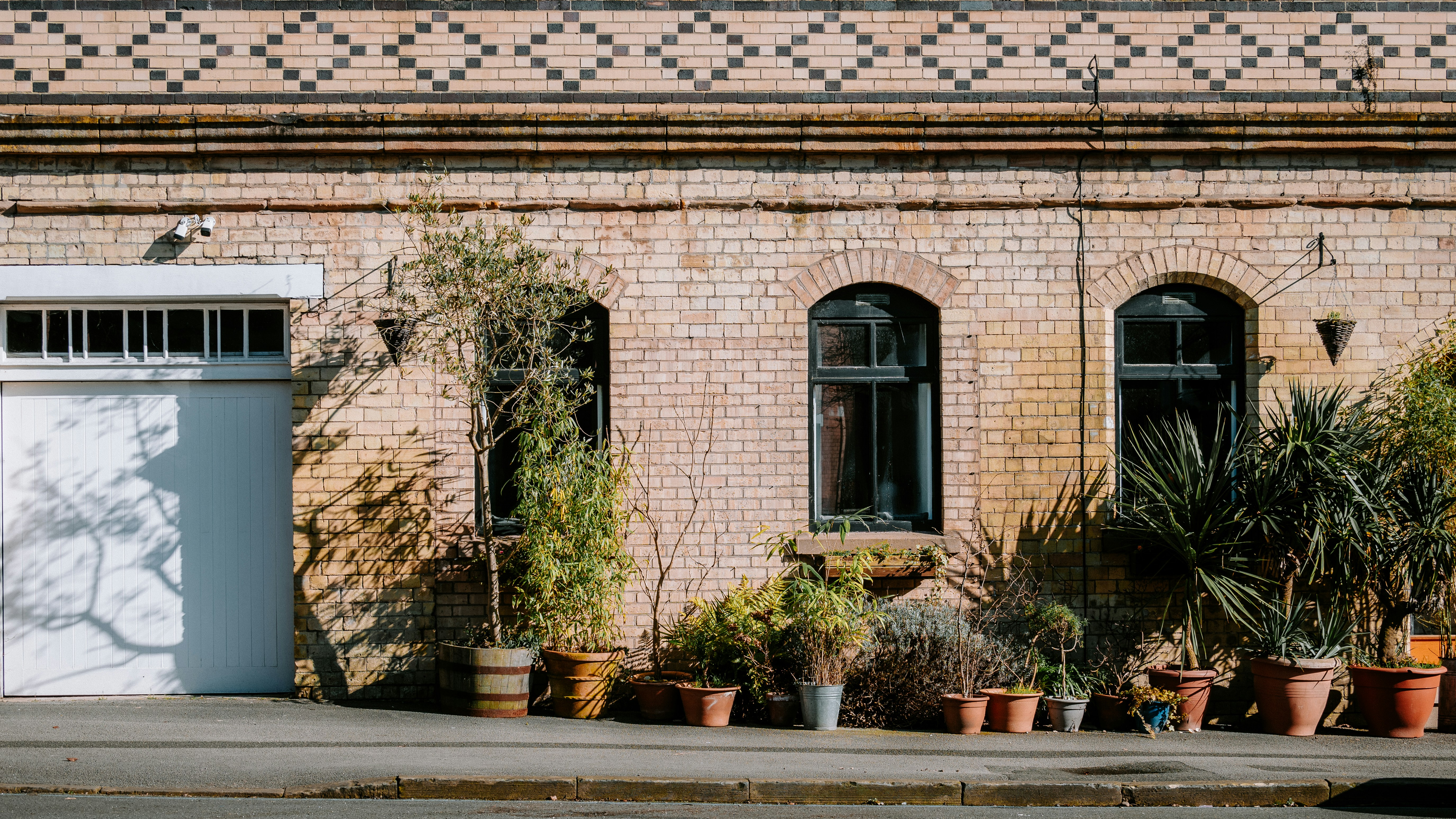 A brick building with potted plants in front of it photo – Free City ...