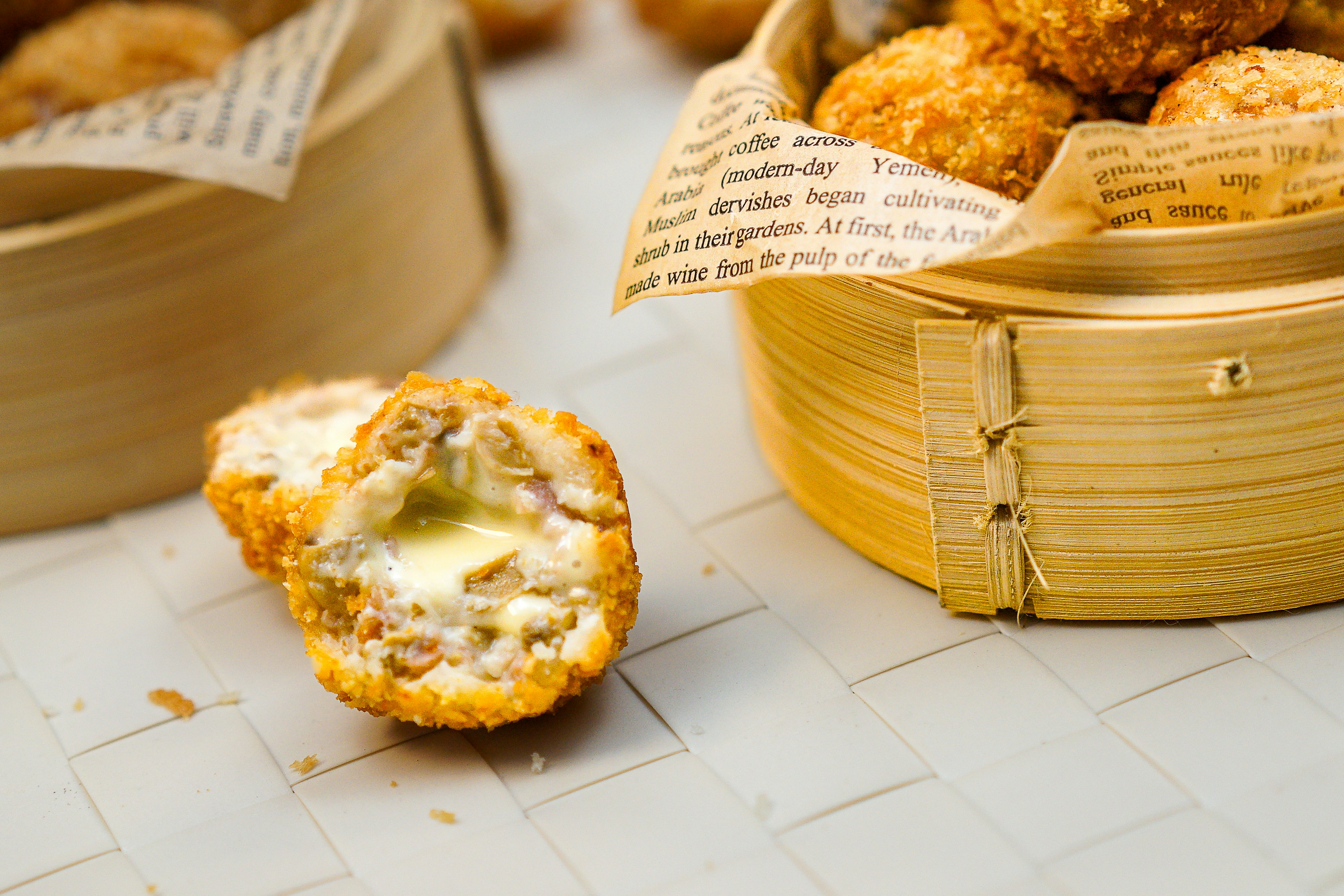 Crispy golden spheres with gooey cheese filling, resting on a wicker mat beside a bamboo basket.