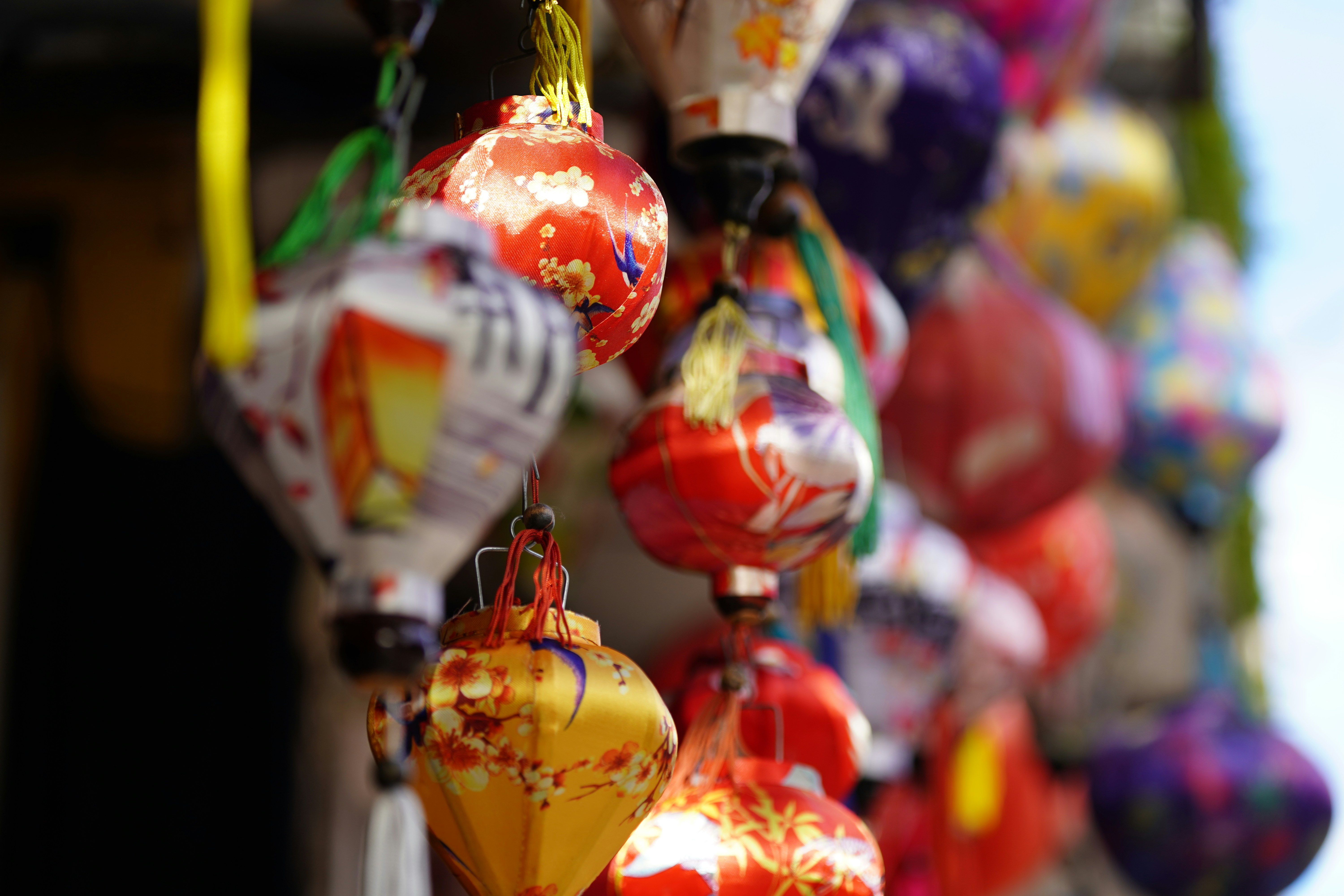Colorful lanterns with floral patterns hanging in a lively street setting.