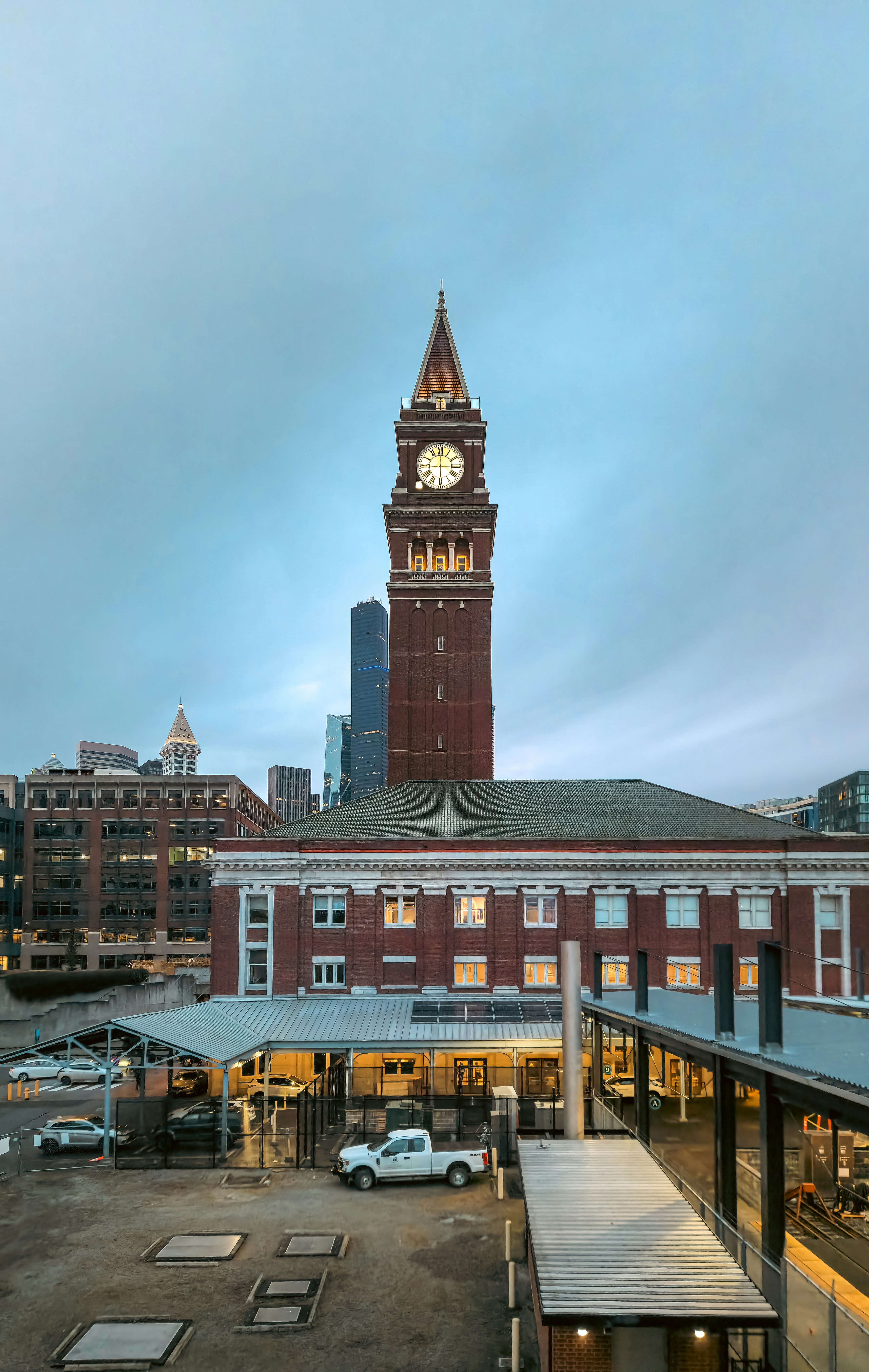 Clock Tower Spire Framing a Brick Campus Against a Modern City Skyline