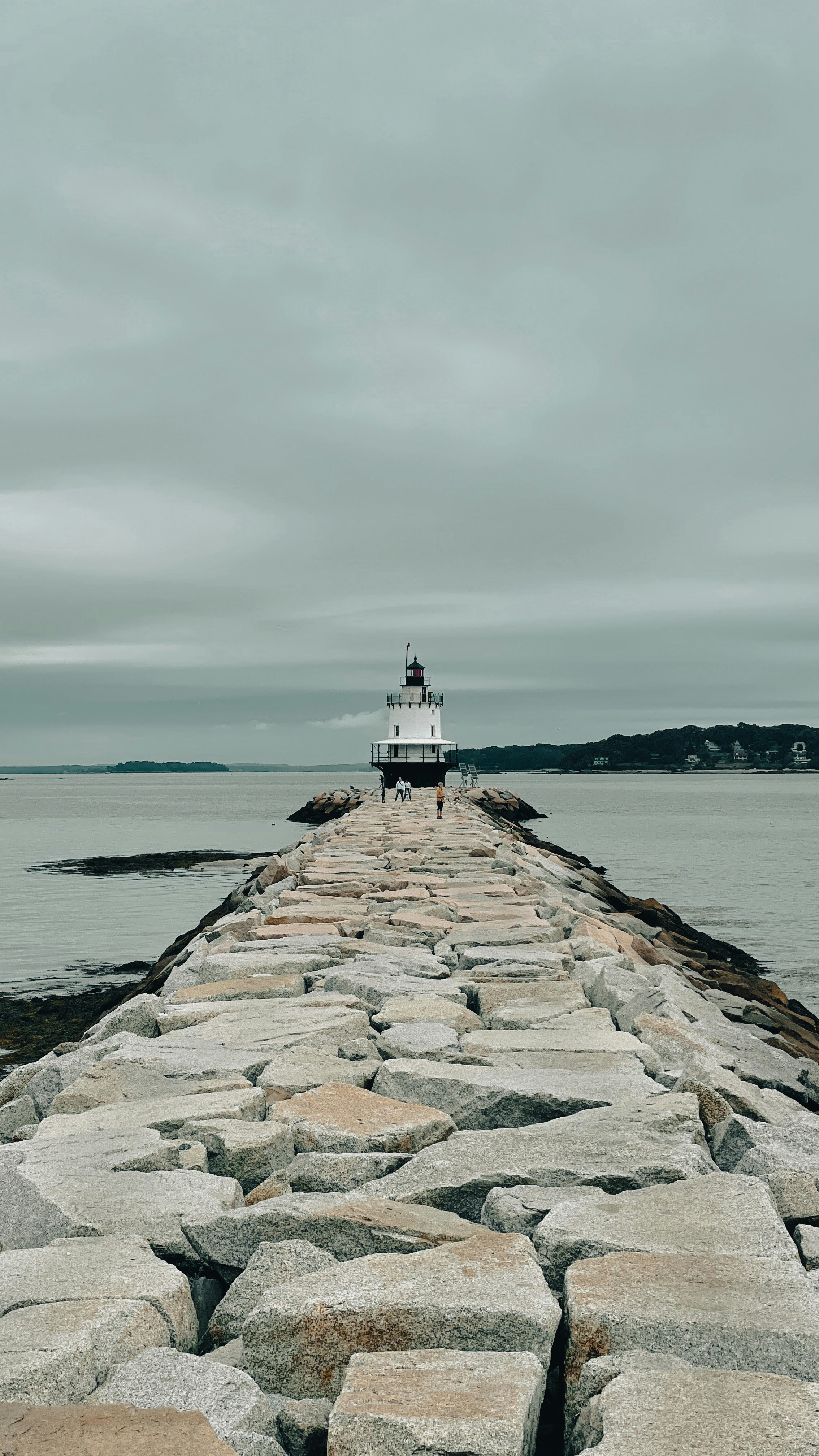 A lighthouse at the end of a stone path.