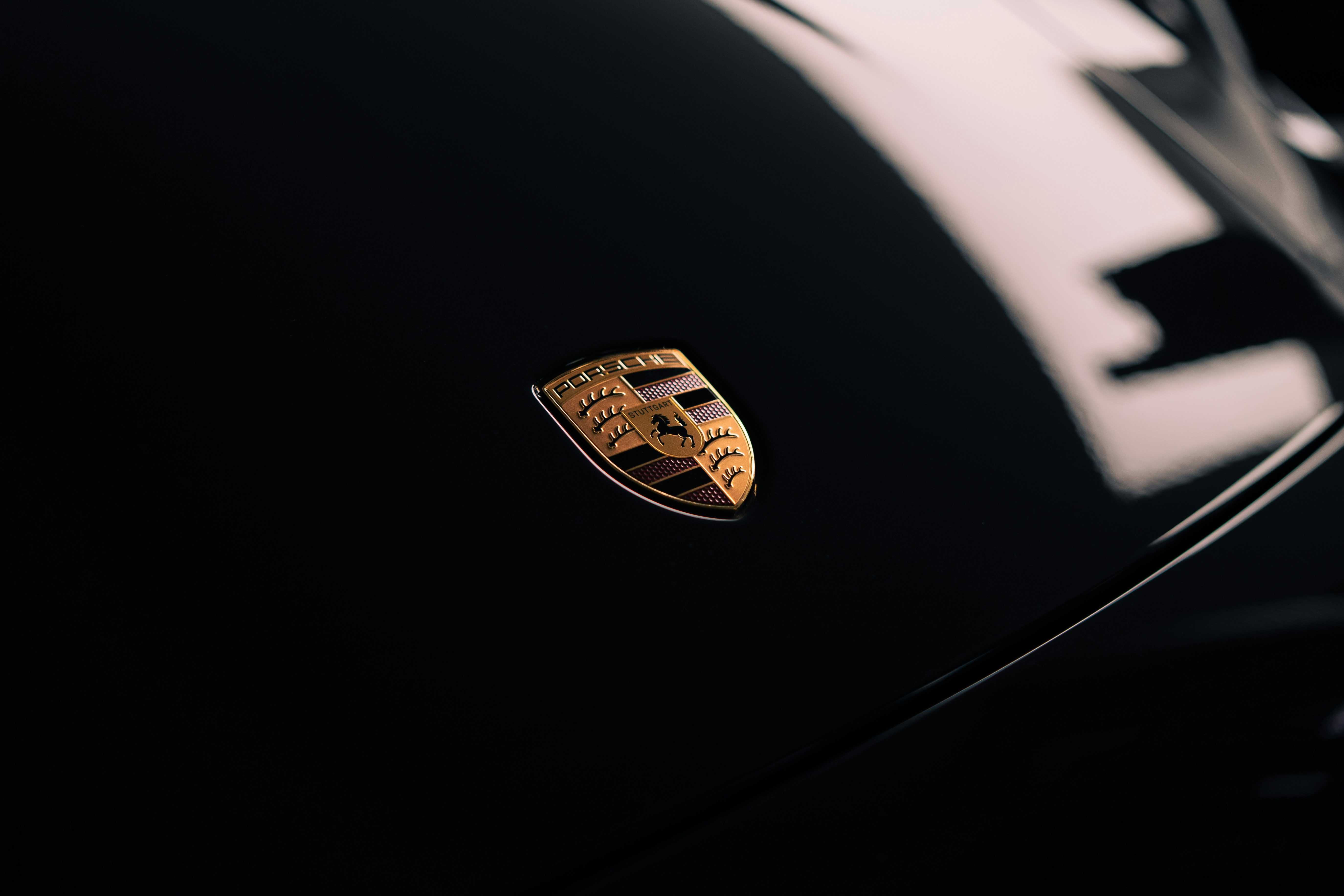 A porsche emblem shines on a black car. photo – Free Wallpaper Image on ...