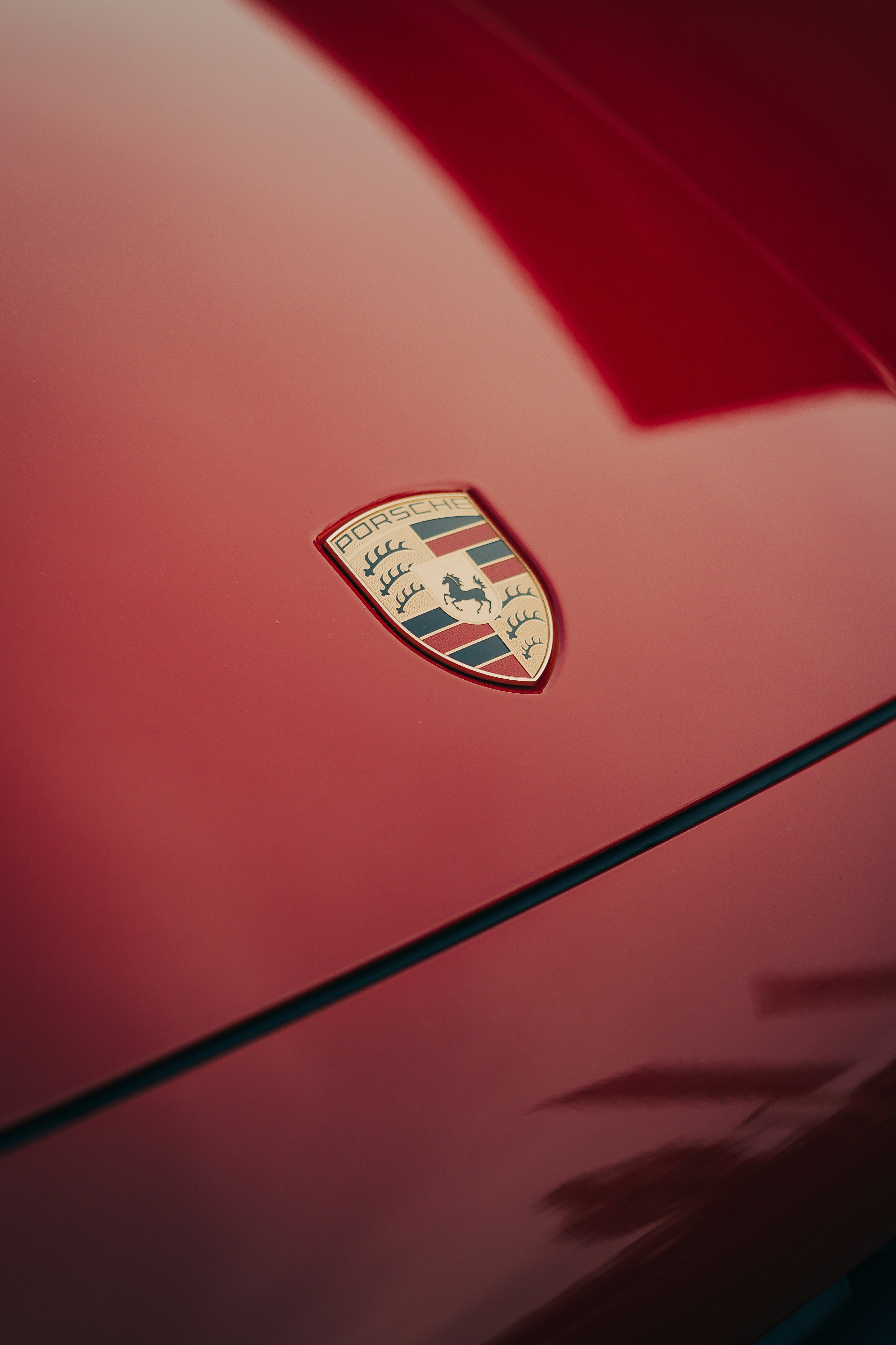 A porsche logo is seen on a red car. photo – Free Wallpaper Image on ...