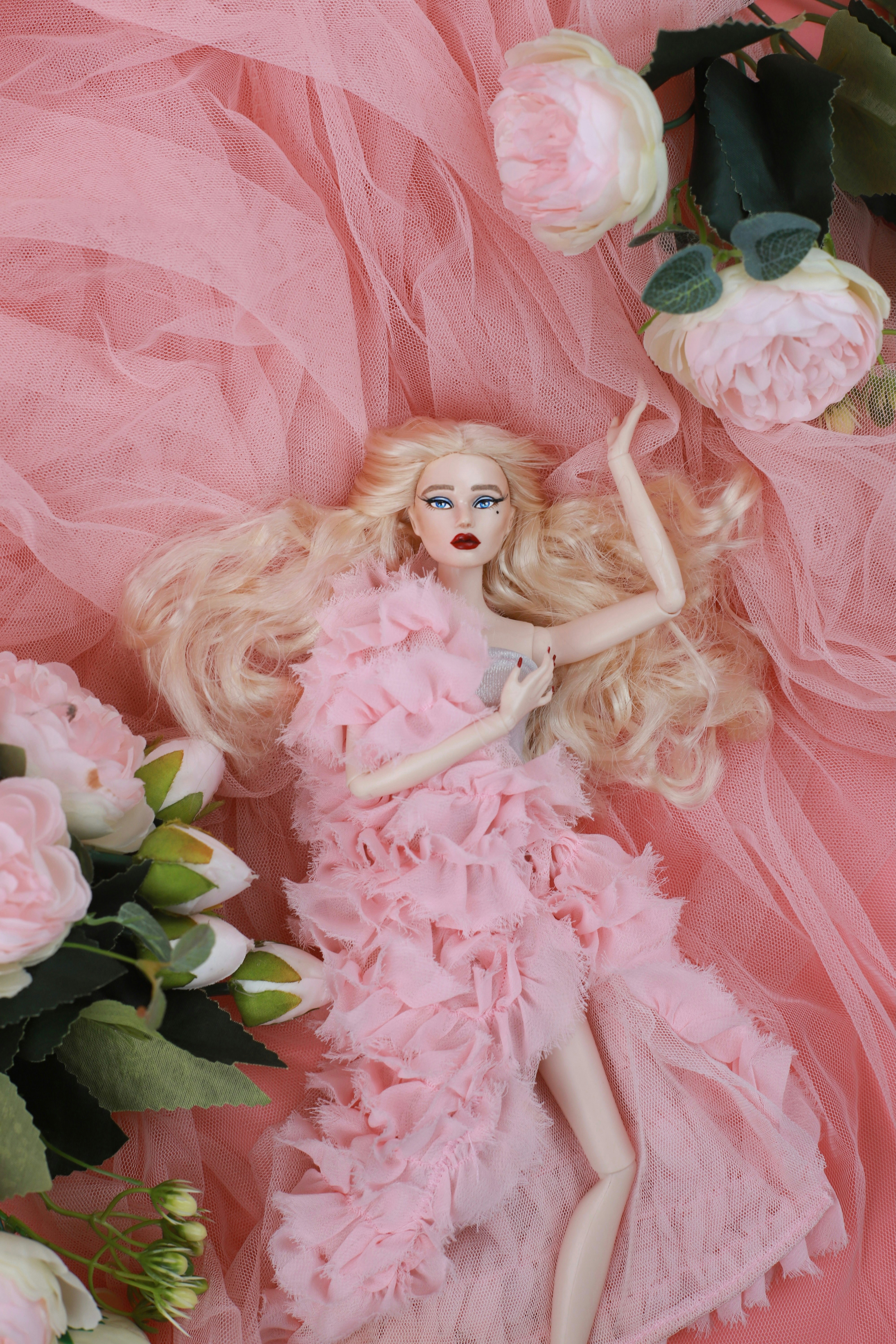 A barbie doll laying on a bed of roses photo – Free Blossom Image on ...