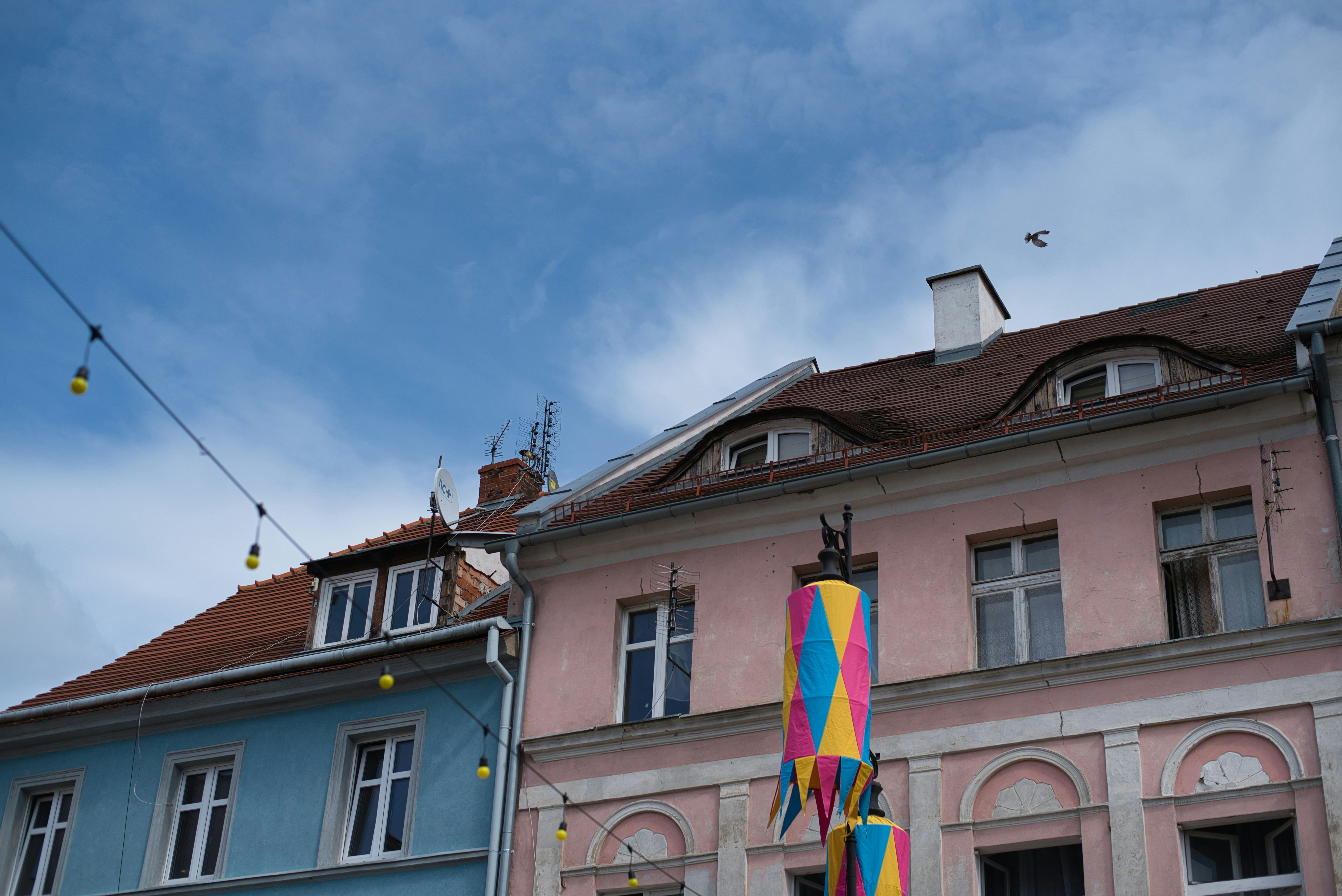 Geometric Prism Tower Among Pastel Townhouses Under a Clear Sky