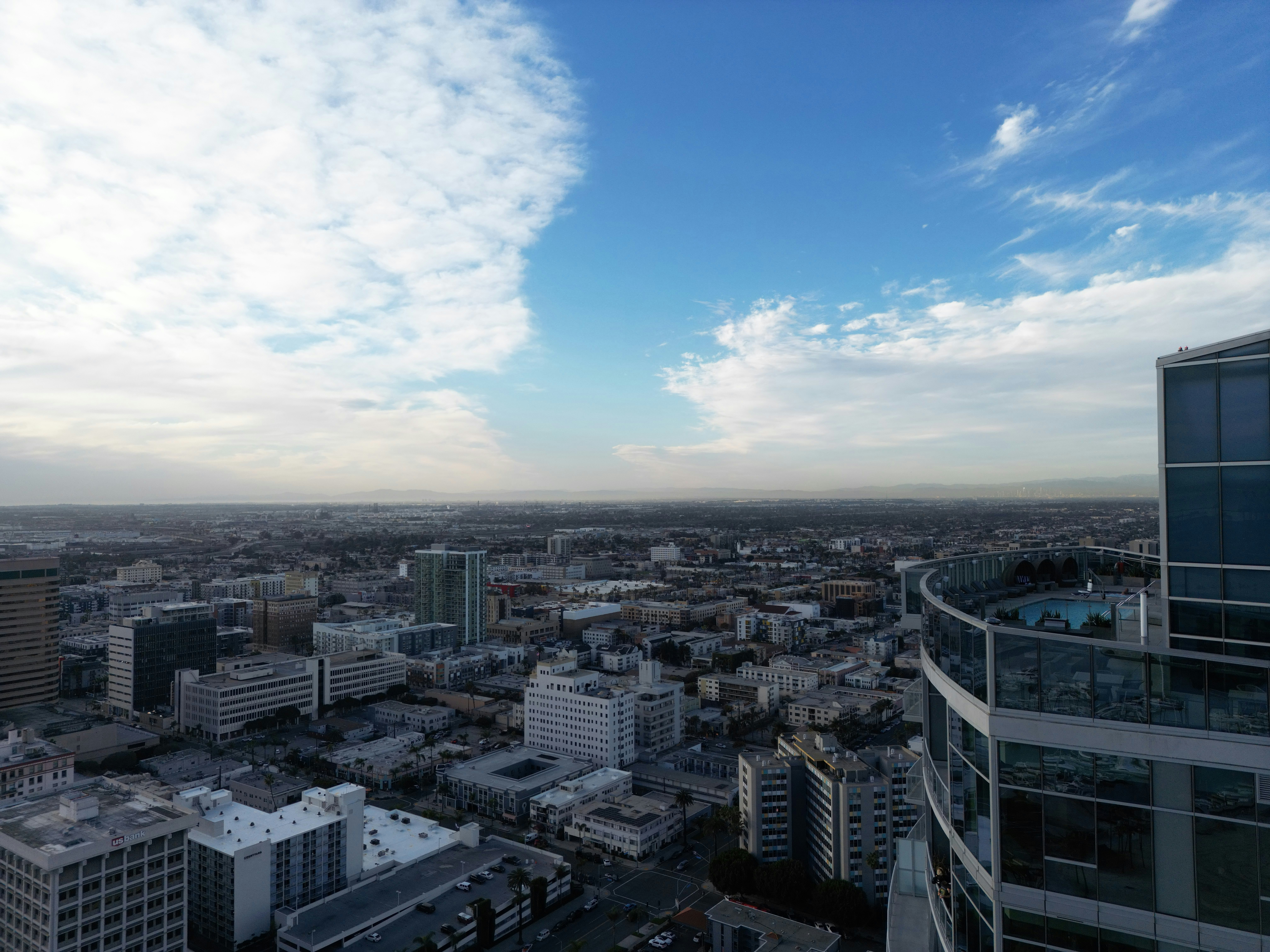 Cityscape with a modern high-rise foreground and vast skyline under scattered clouds.